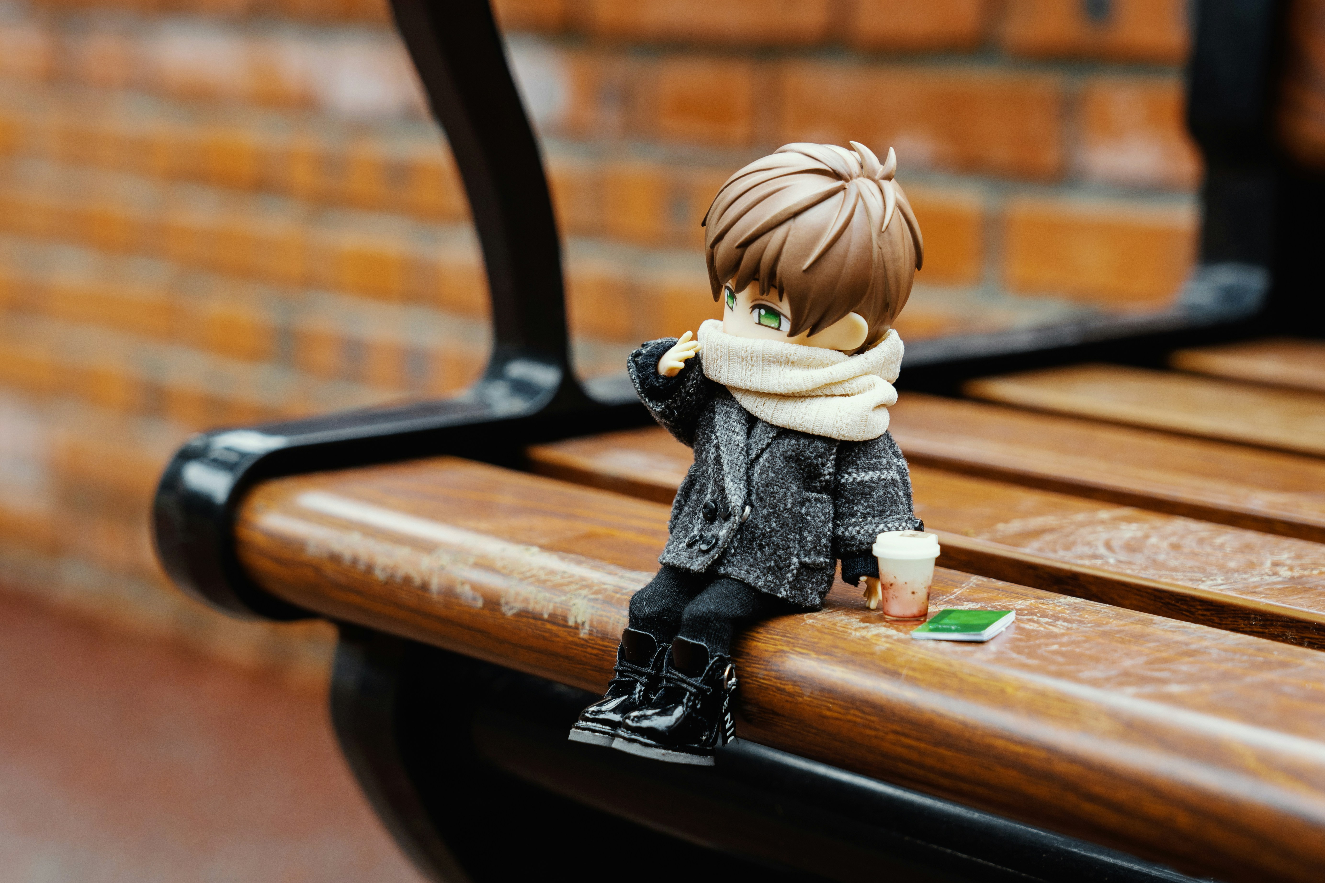 Cozy stare: a miniature figure soaks in autumn street light on a wooden bench