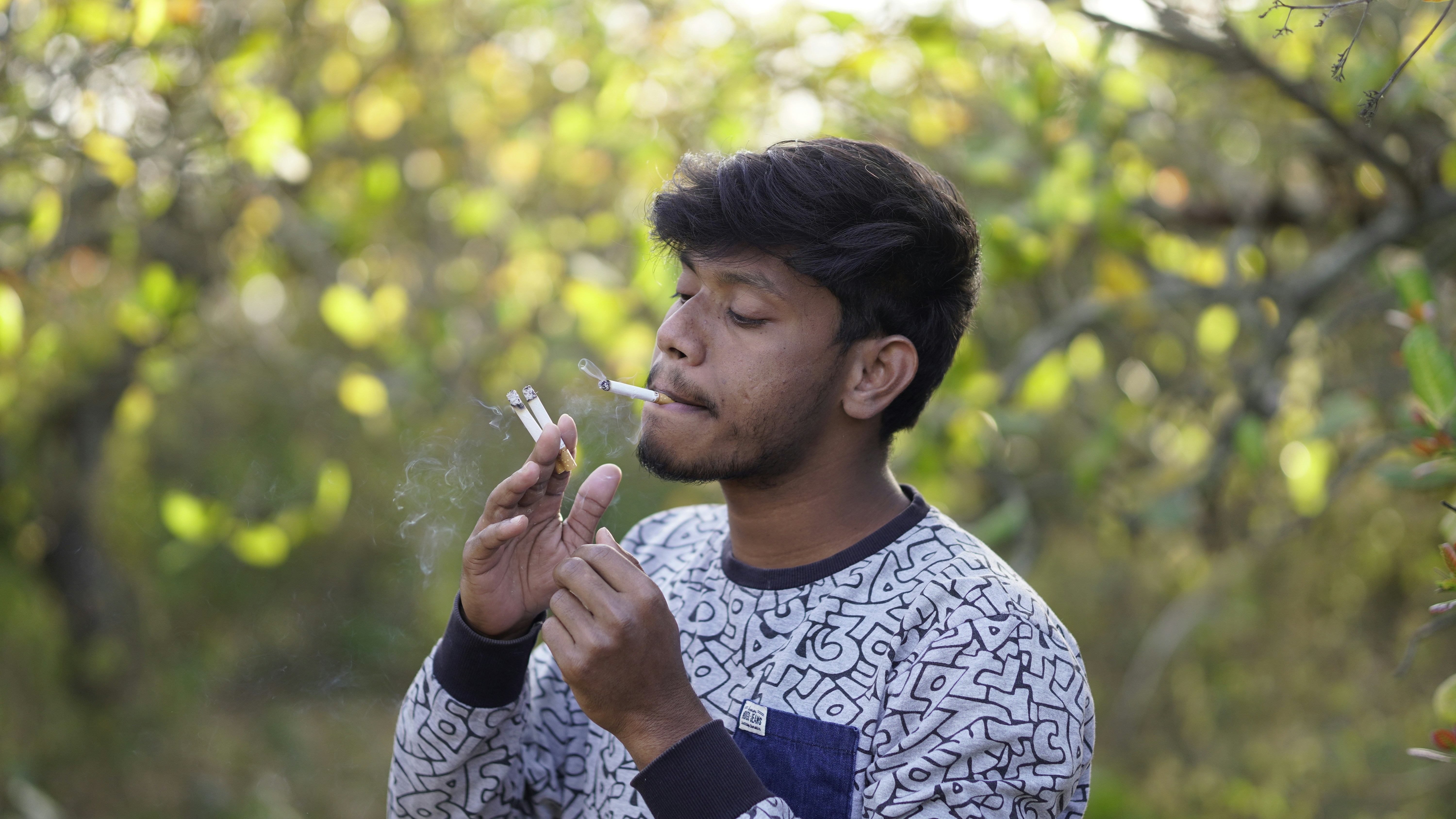 A man smoking a cigarette in a forest photo – Free India Image on Unsplash
