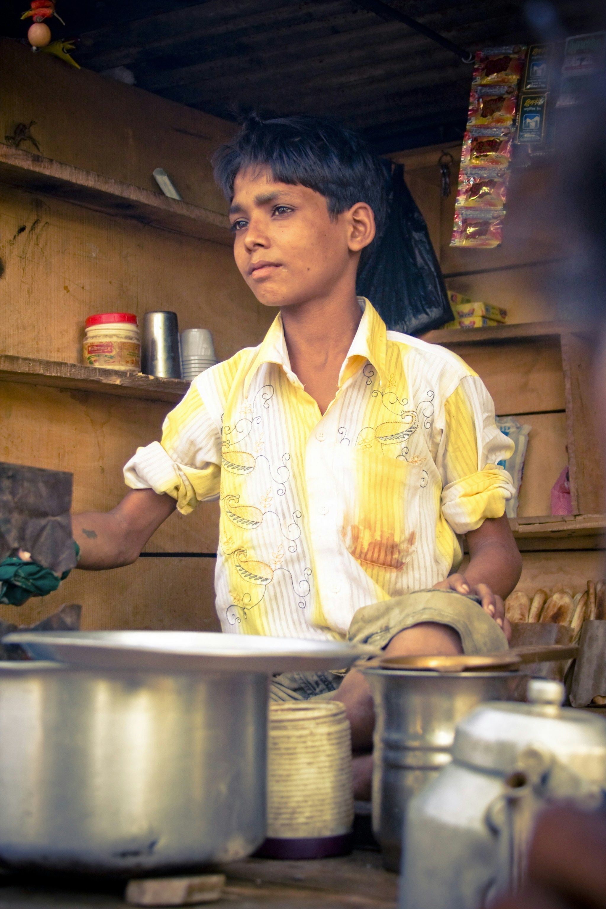 A young boy sitting in a kitchen with pots and pans photo – Free India ...