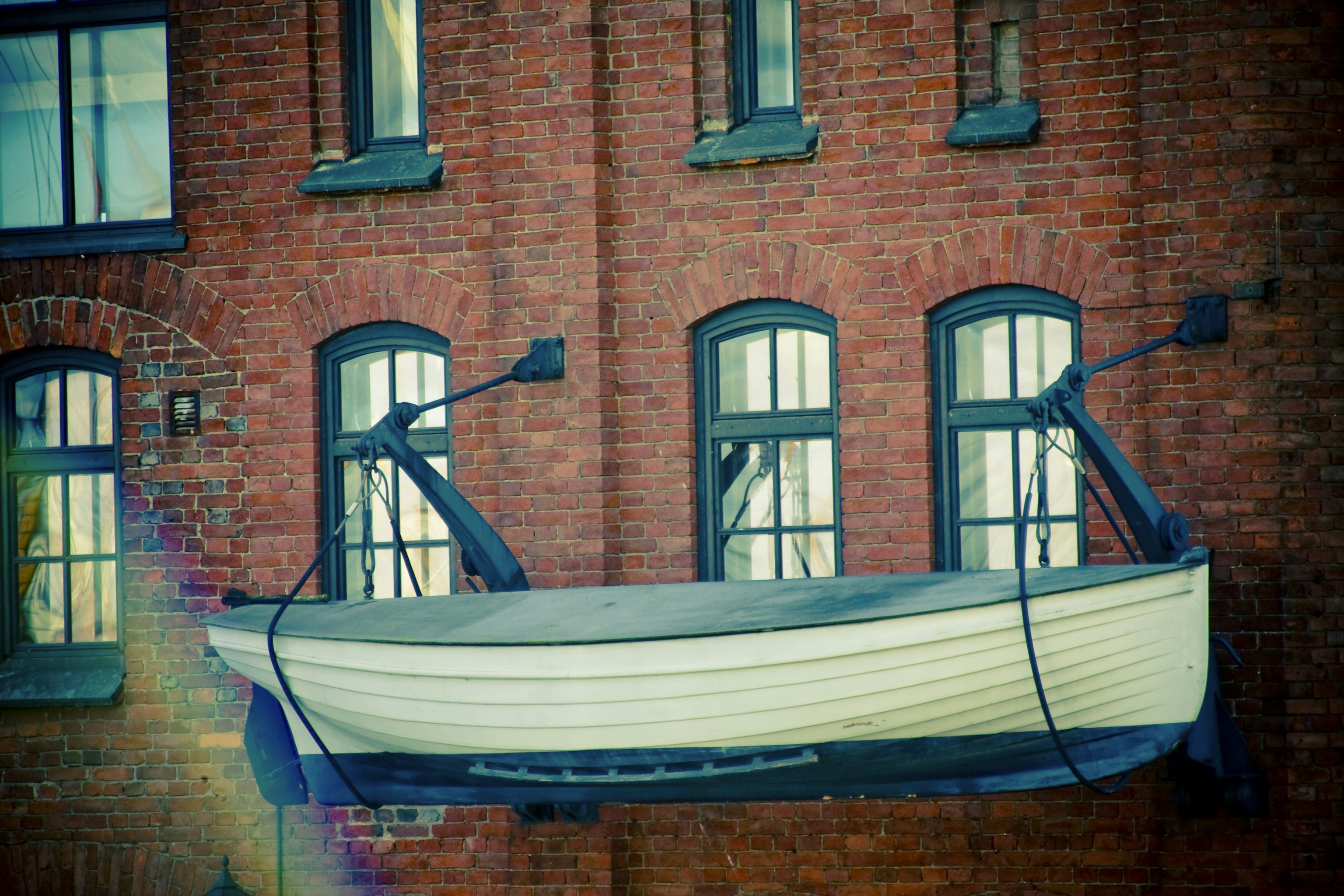 Suspended White Hull: a maritime sculpture on a brick wall