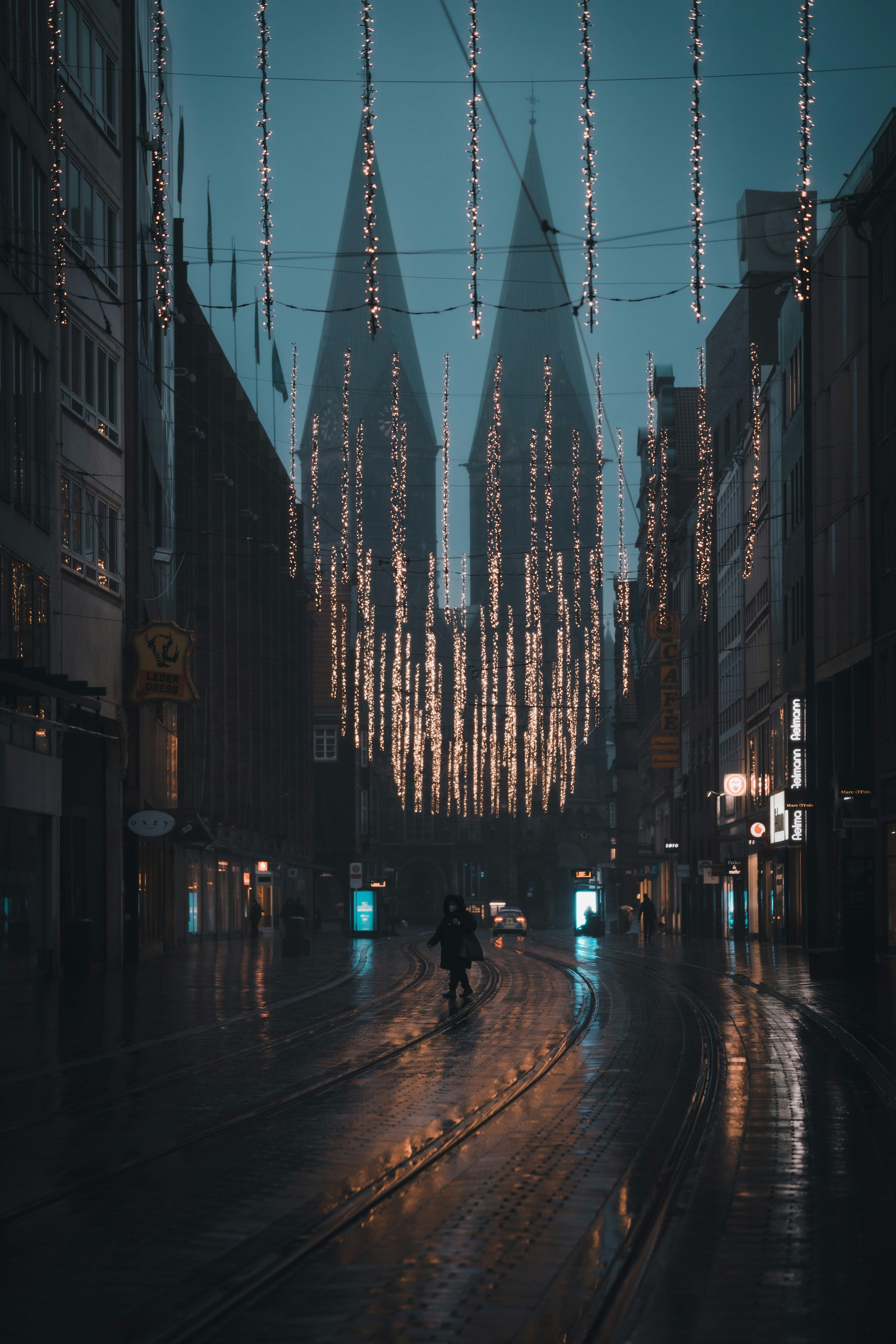 Icicle-Lights Over a Rain-Slick Avenue: A Lone Pedestrian Crosses the Glow