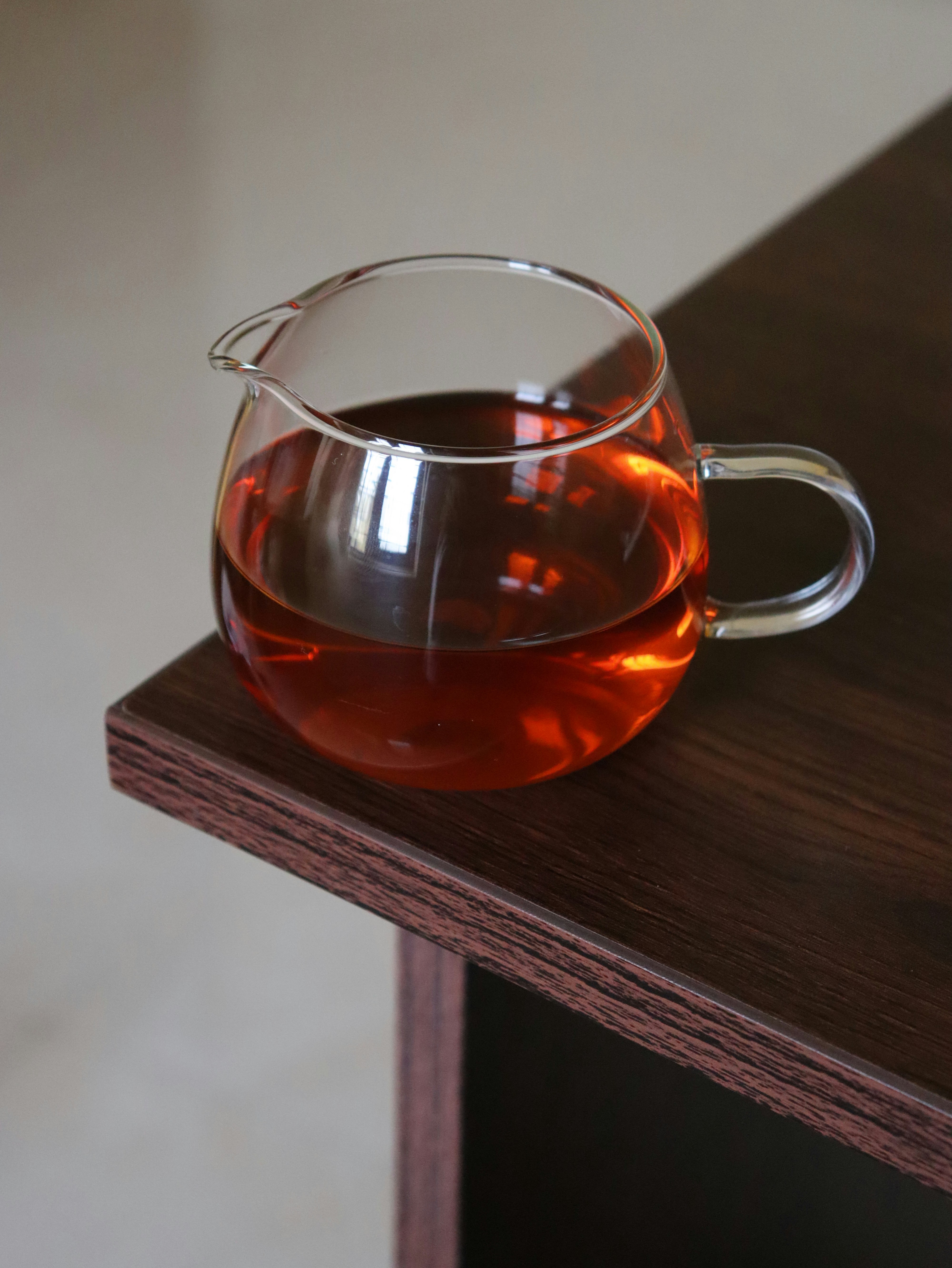 A glass pitcher of tea sitting on top of a wooden table photo – Free ...