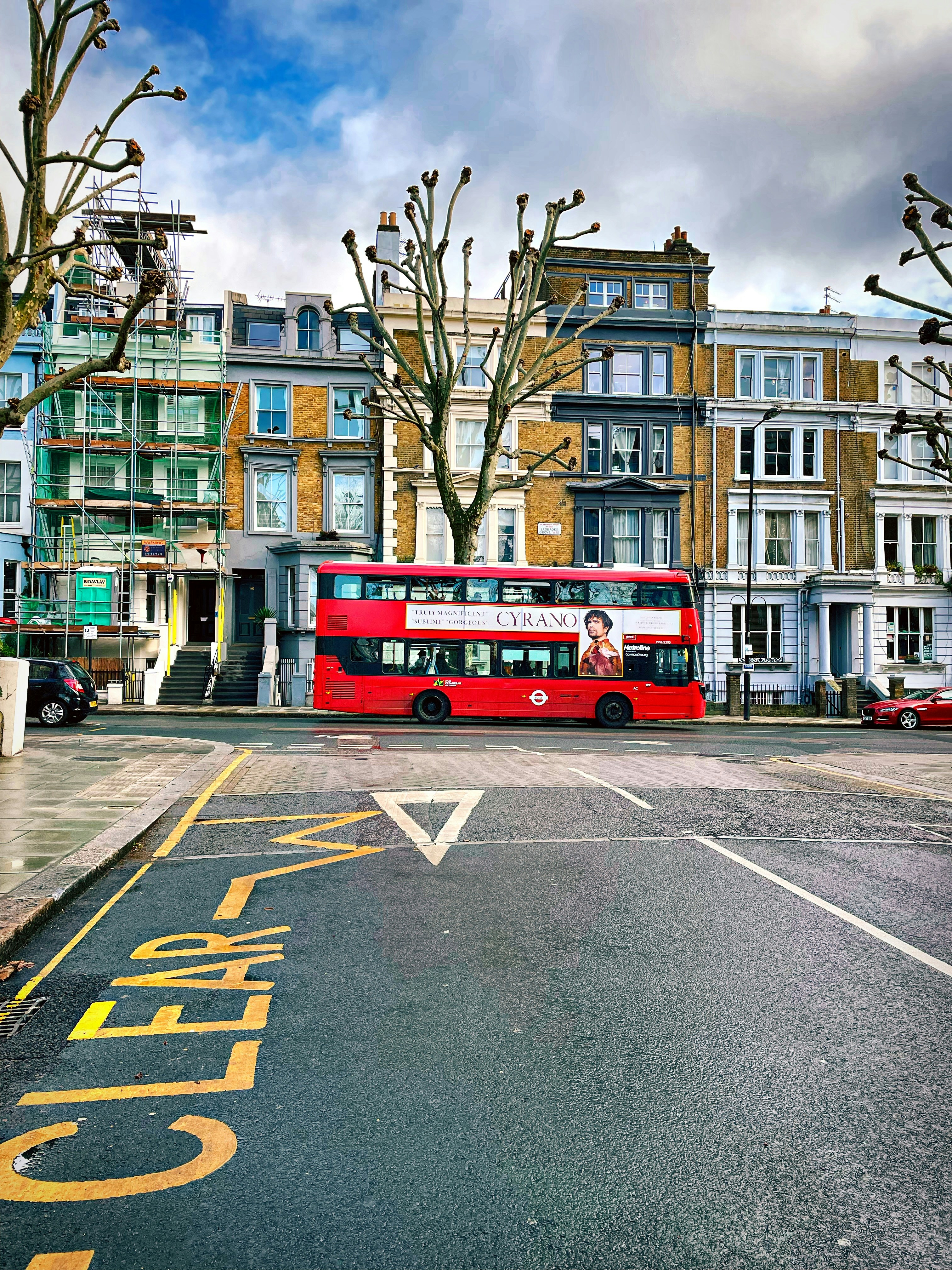 Crimson Double-Decker Pauses Along a London Terrace Row