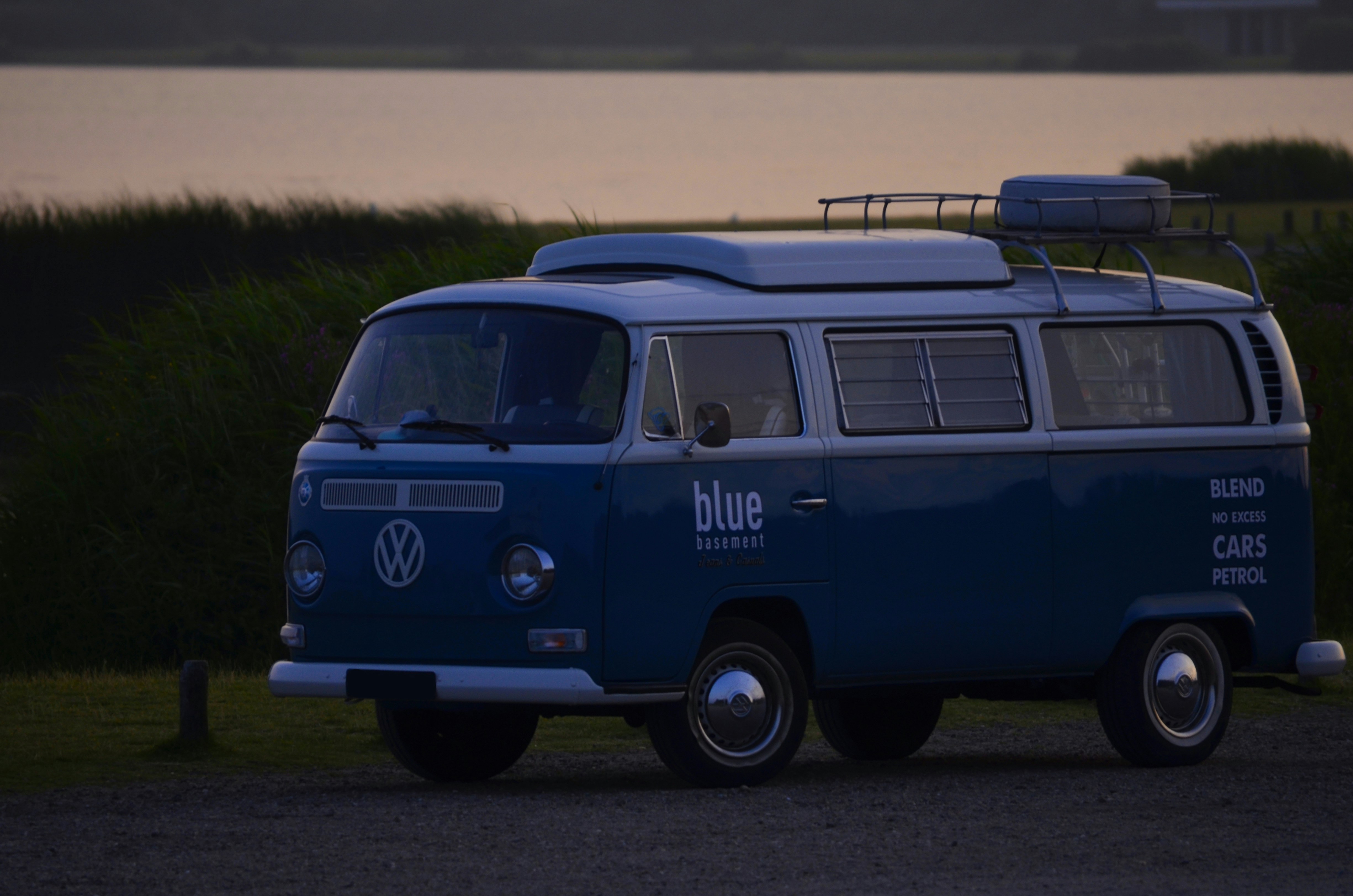 A blue vw bus parked in front of a body of water photo – Free Van Image ...