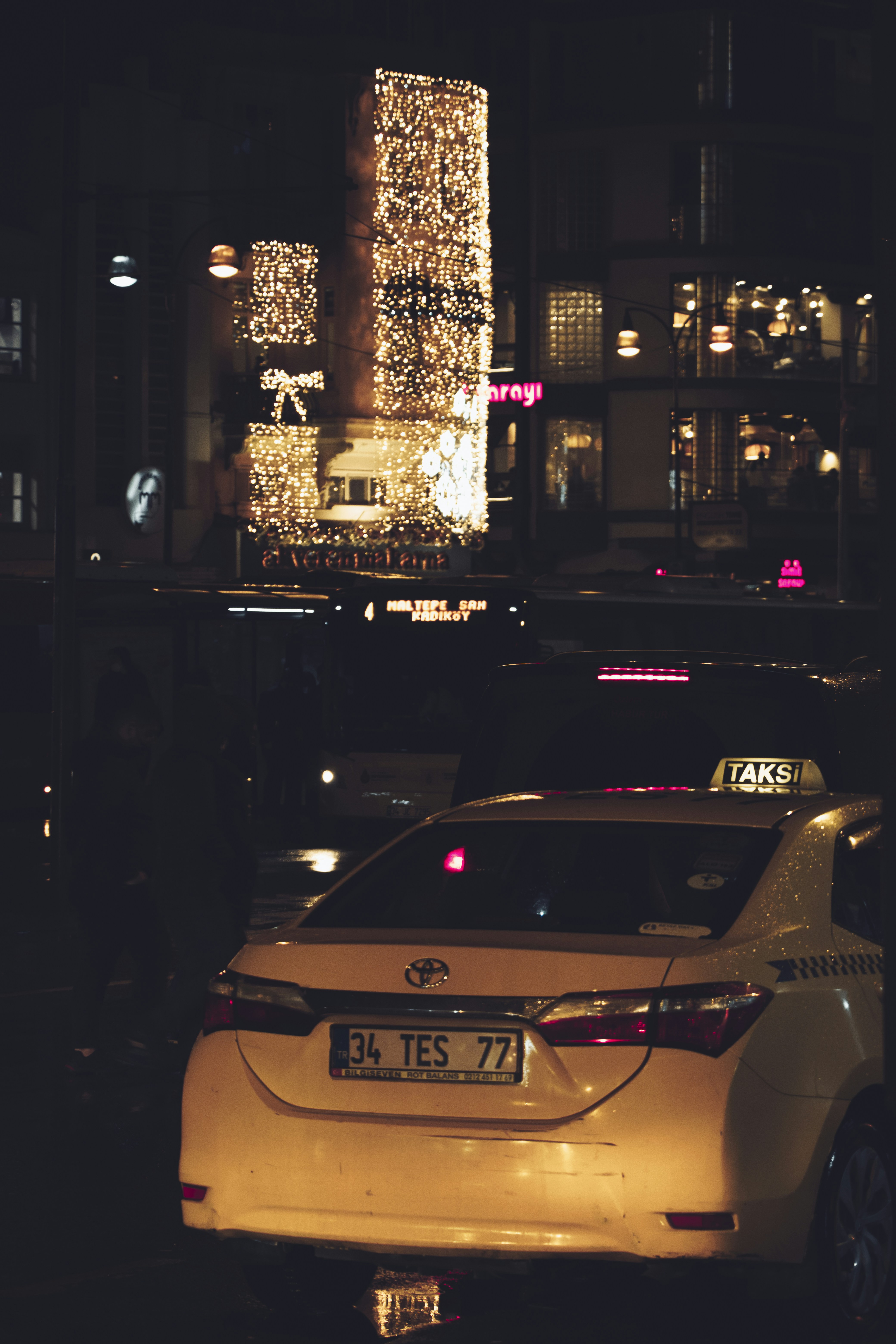 Taxi Under Festive Neon: Night Glow on a Damp City Street