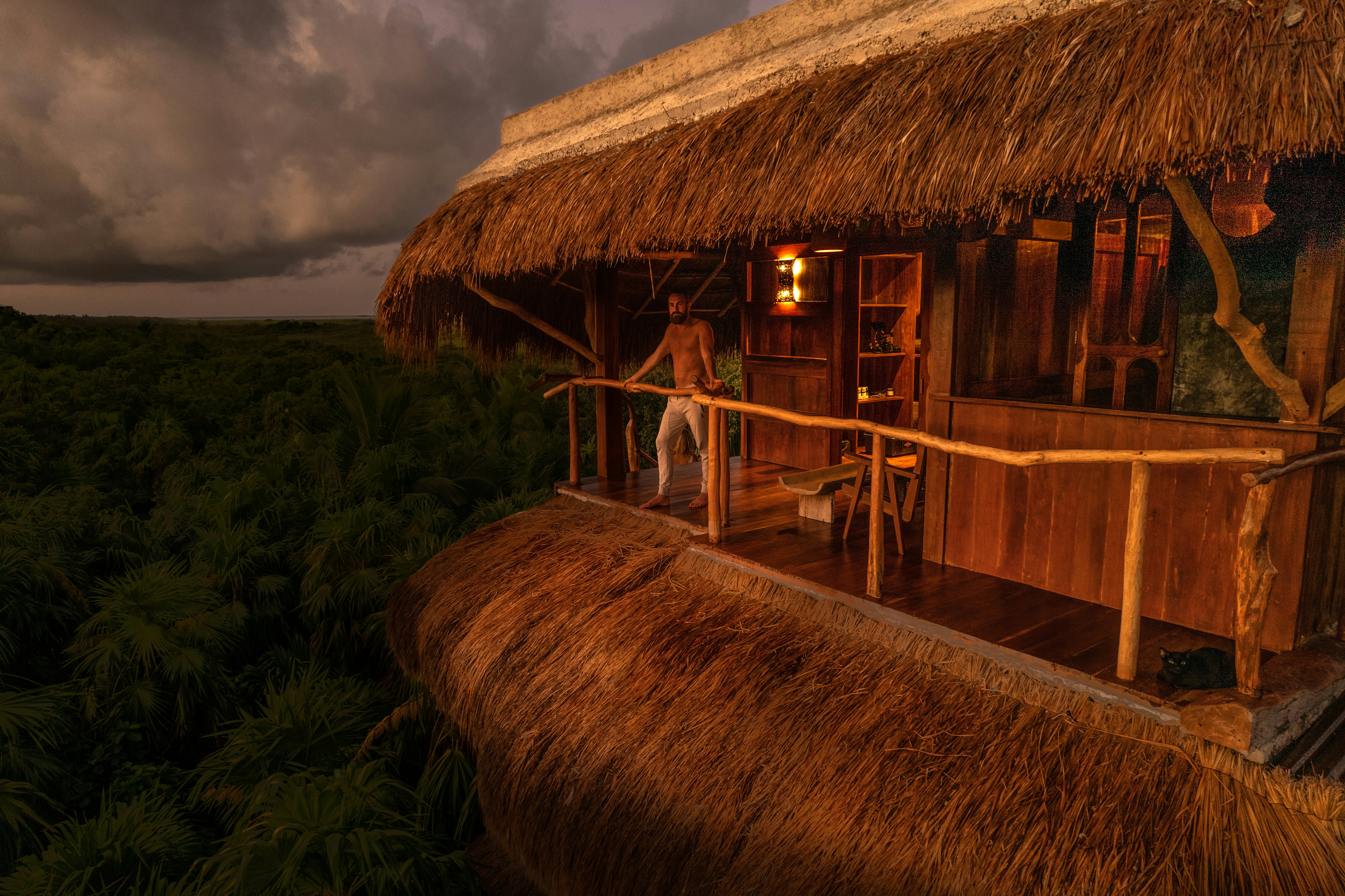 A woman standing outside of a hut with a thatched roof photo – Free ...