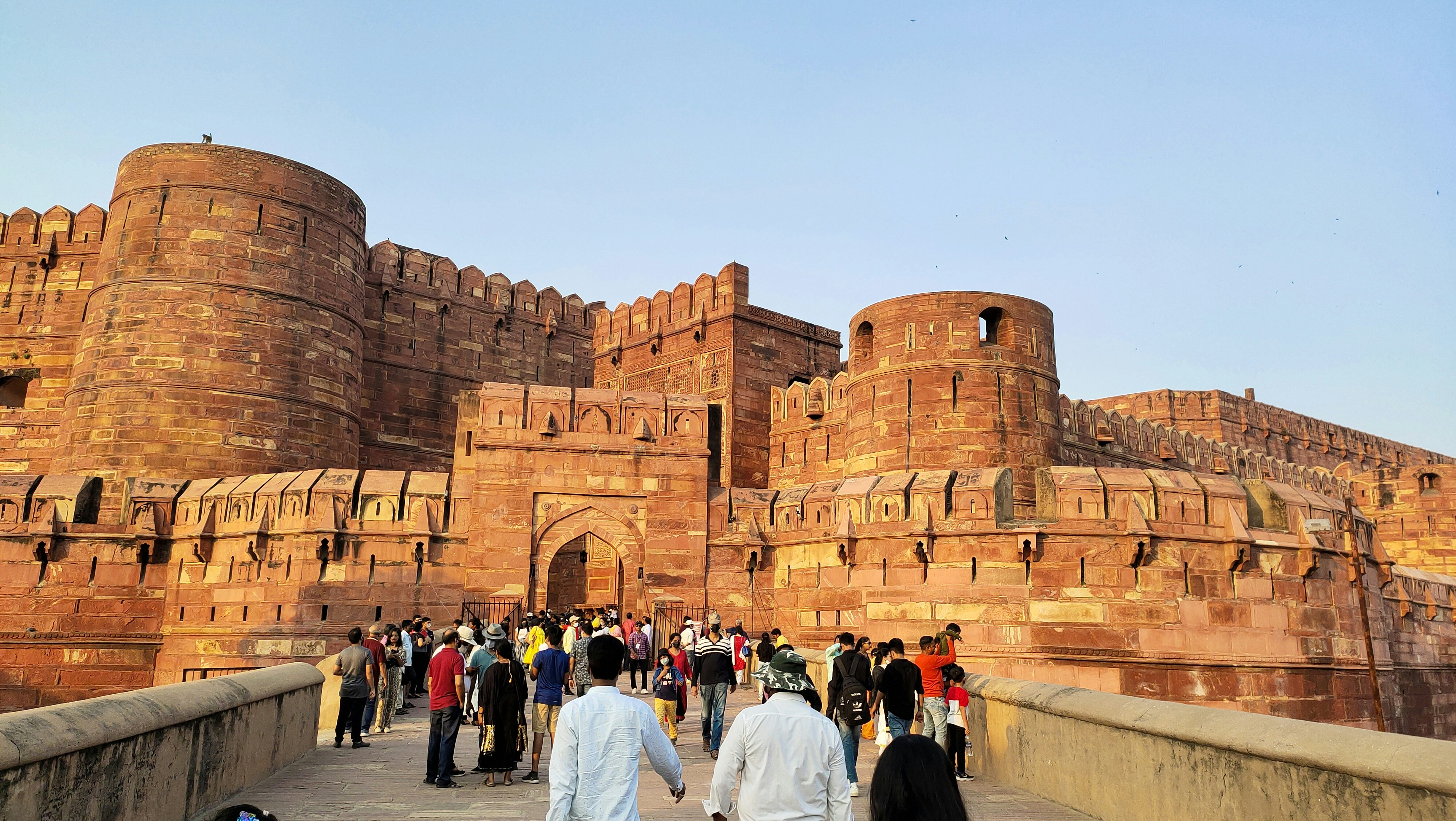 Sunlit Gates: Fort Walls and Crowds Crossing the Bridge