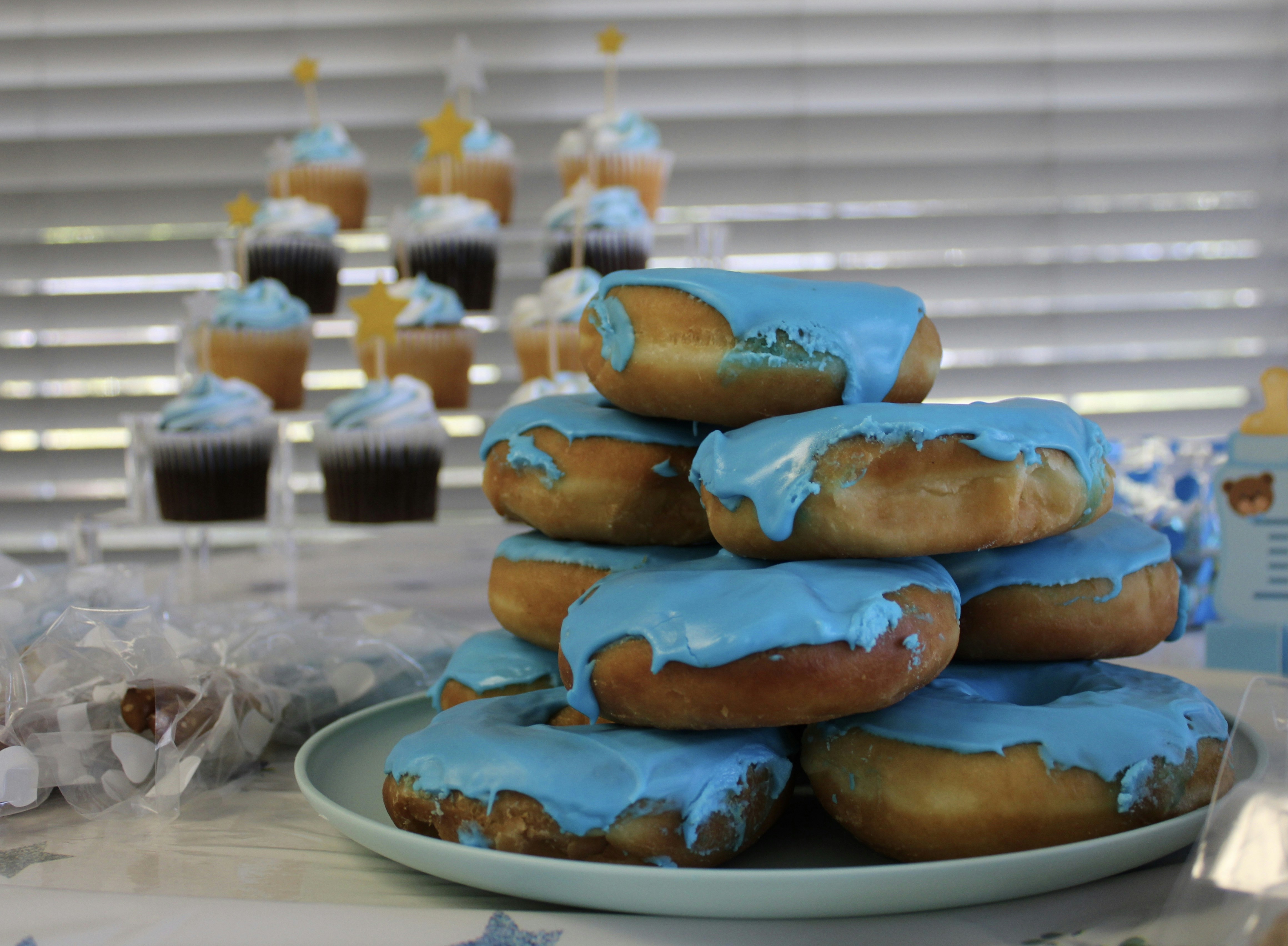 A plate of blue frosted donuts on a table photo – Free Doughnut Image ...