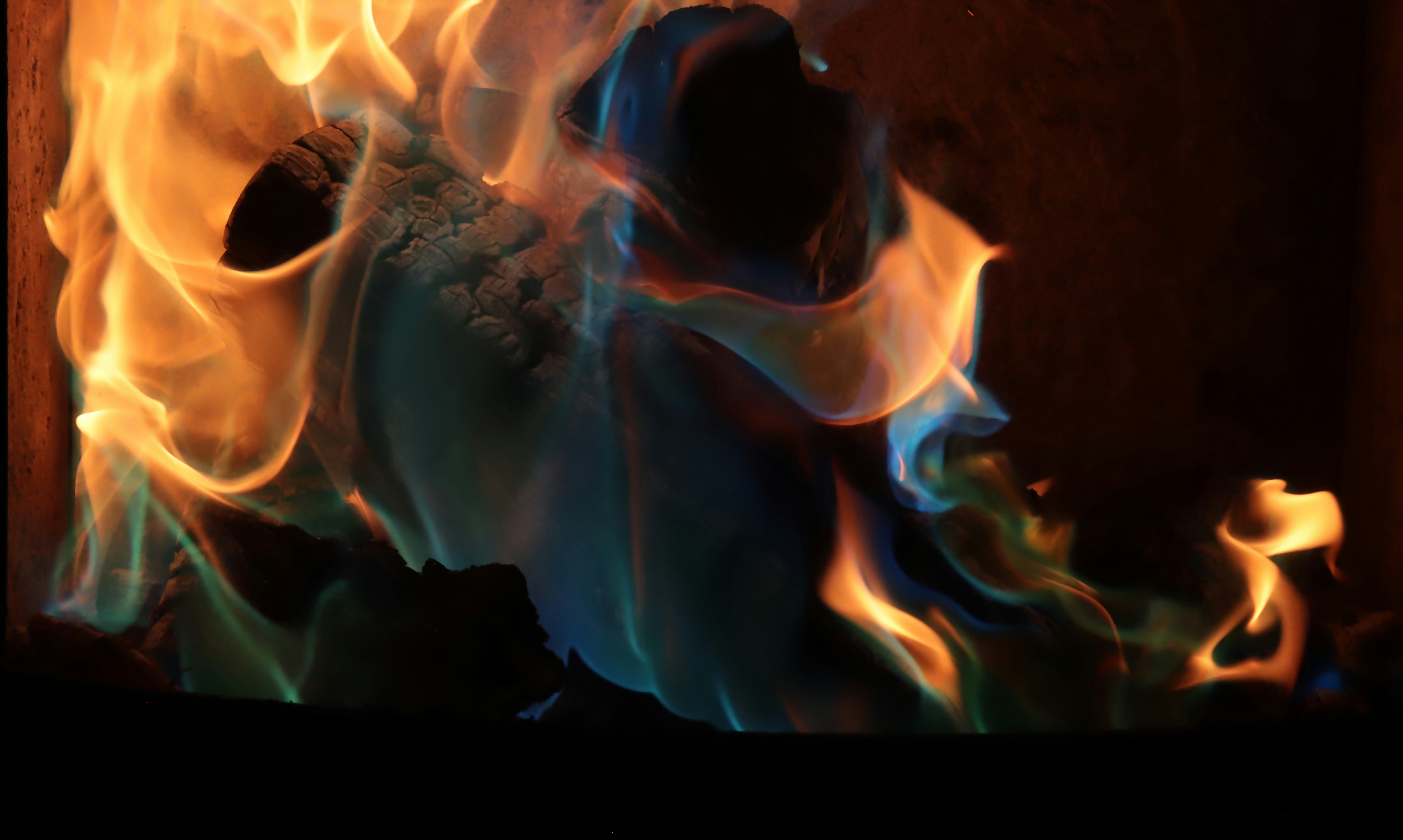 A fire burning inside of a fireplace next to a wall photo – Free Wärme ...