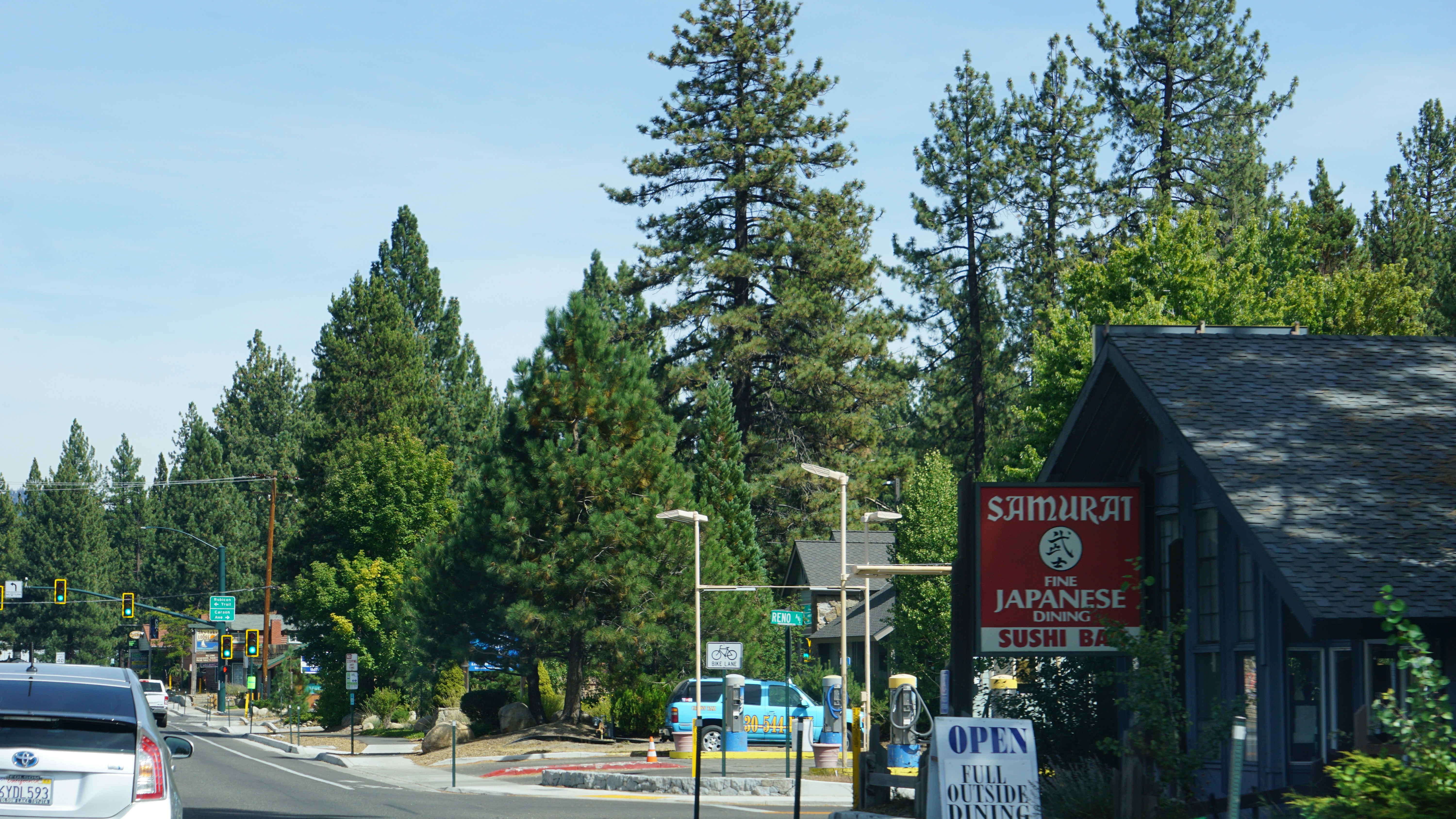 Samurai Japanese Restaurant sign stands prominently along a tree-lined road, inviting diners to explore its sushi offerings.