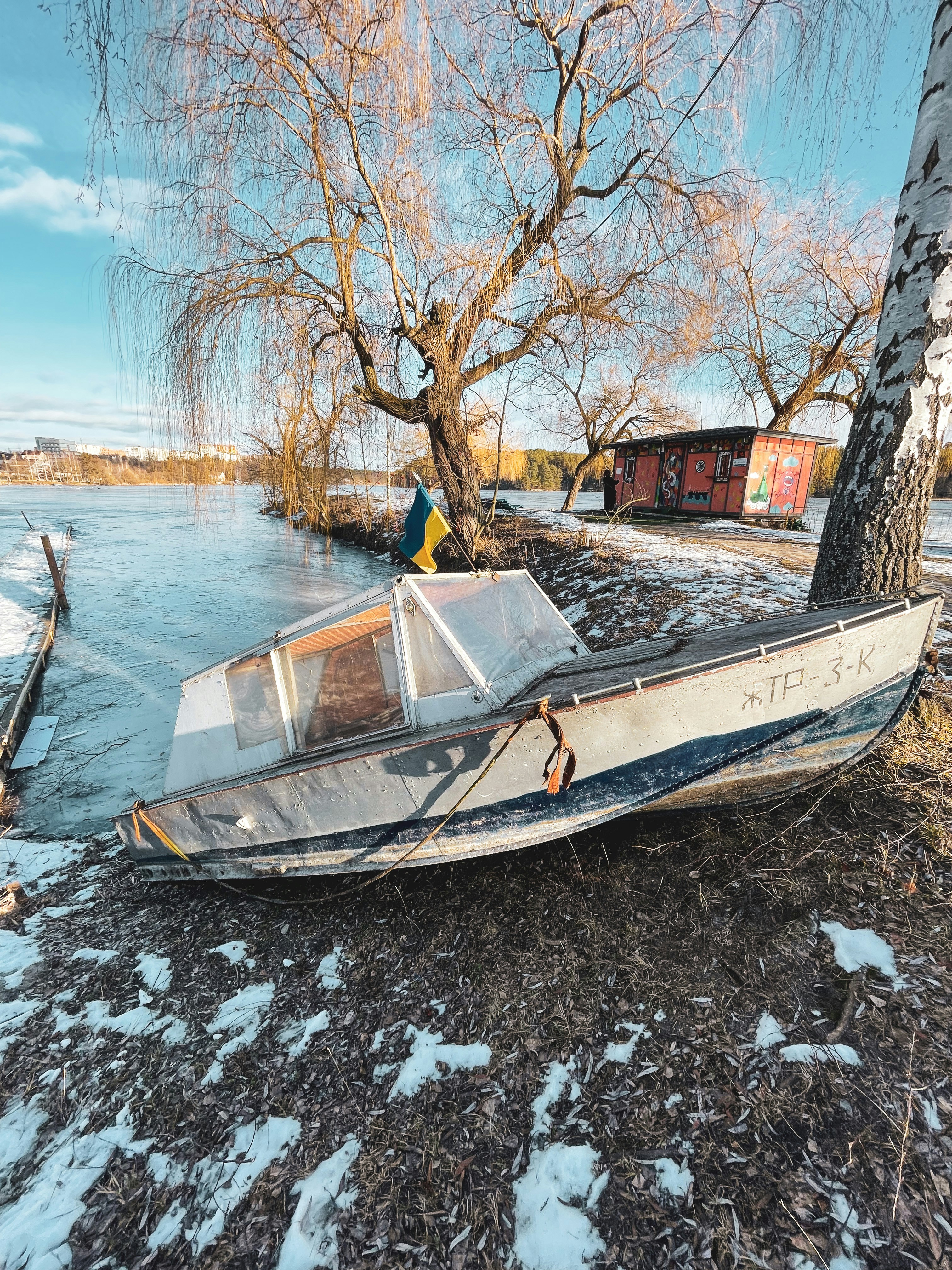 Derelict Cabin by the Icy Shore: A Weathered Boat in Winter Rest