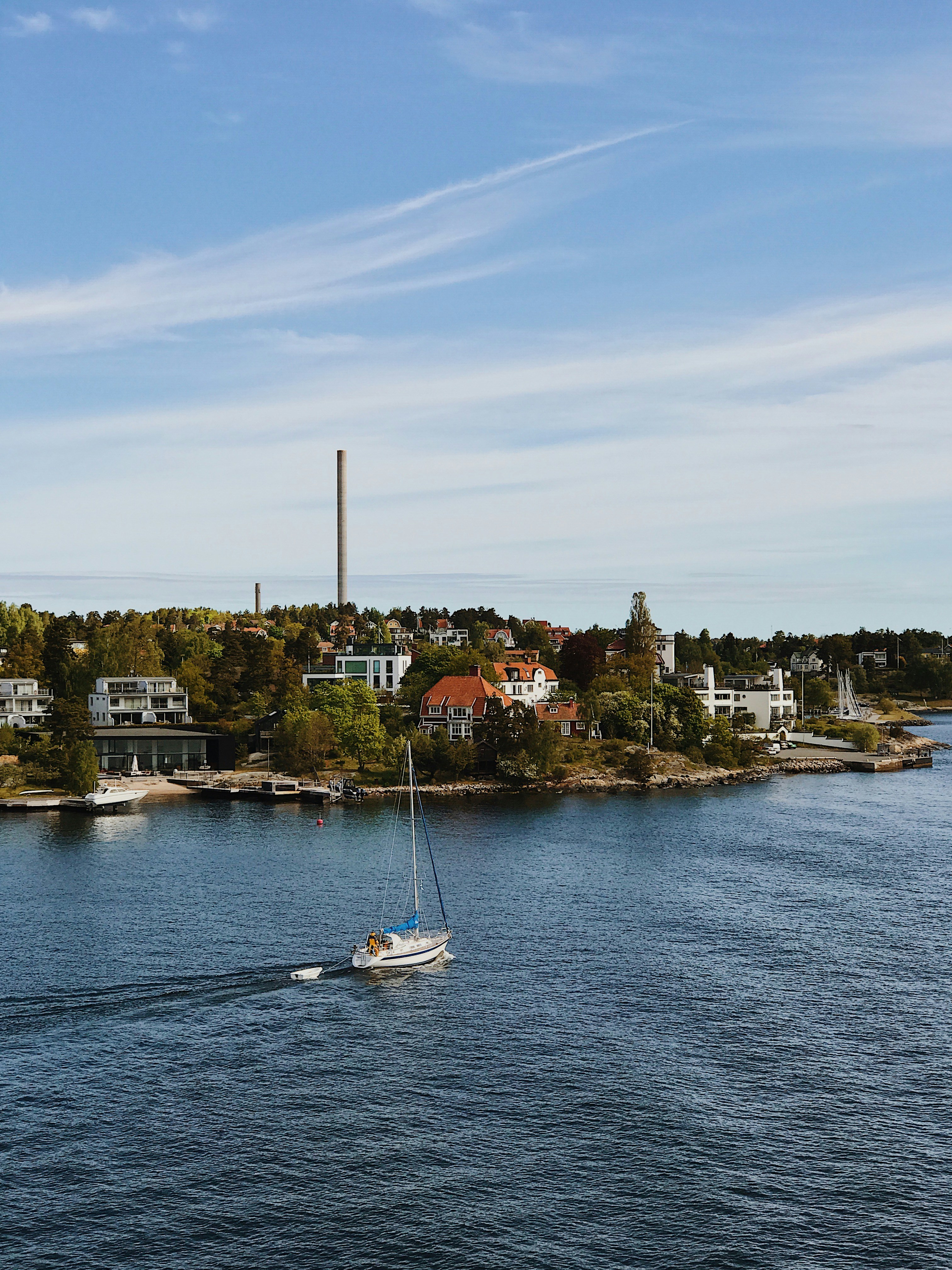 Sloop Drifts Past Waterfront Homes Under a Crisp Day