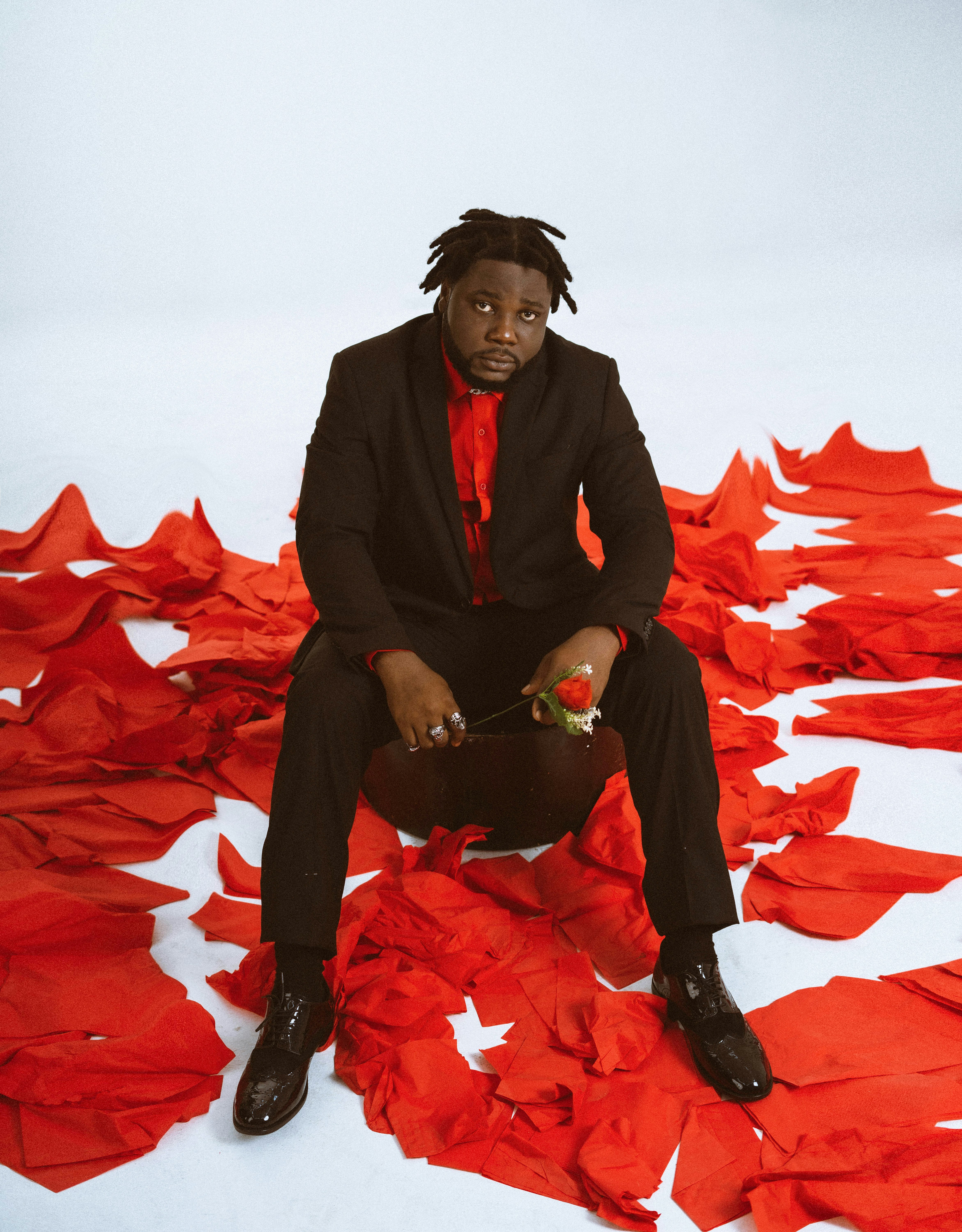 Crimson Carpet Portrait: A Suited Figure Among Red Petals
