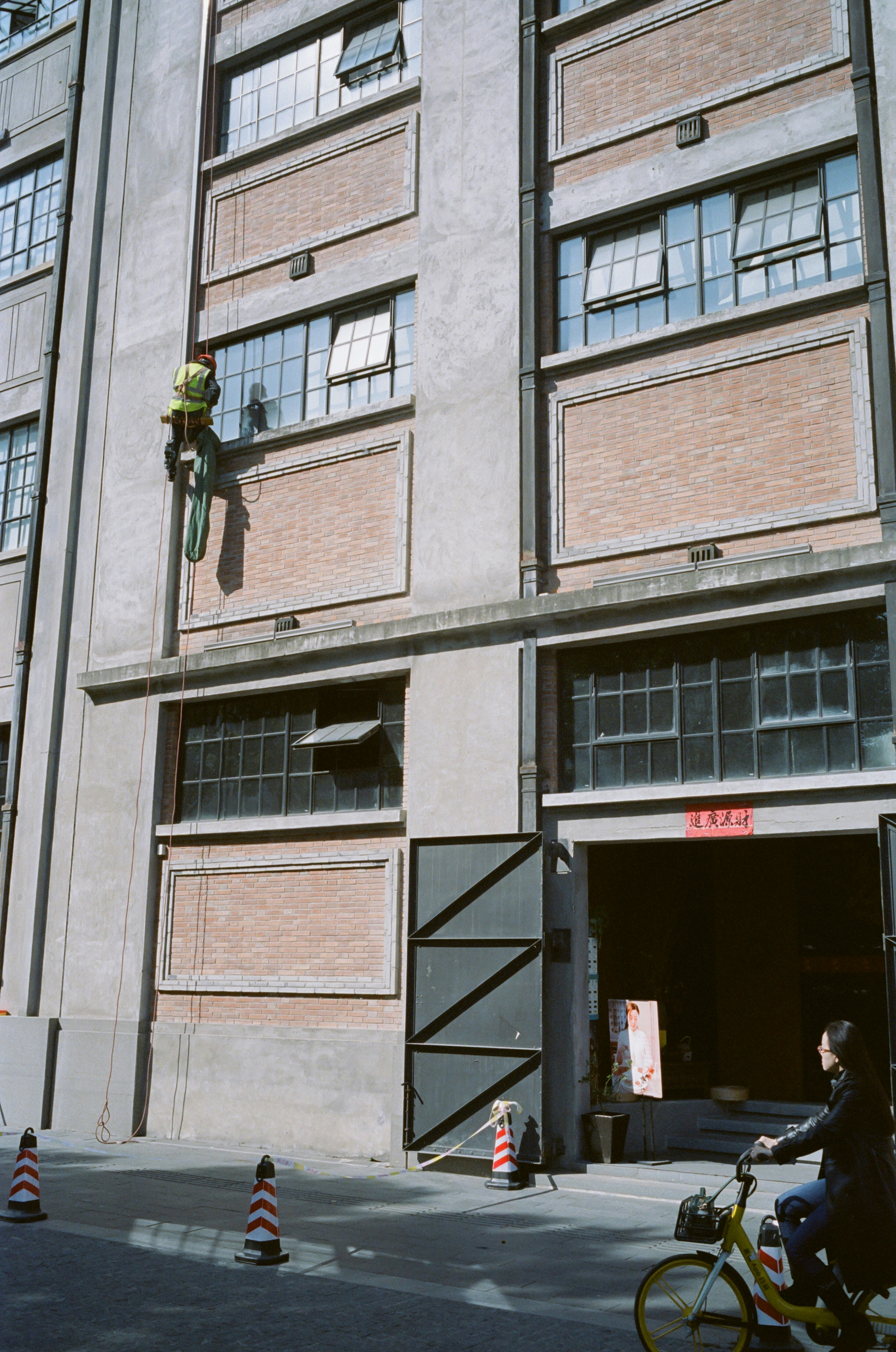 High-rise Ascent: Worker Suspended Against a Brick Facade