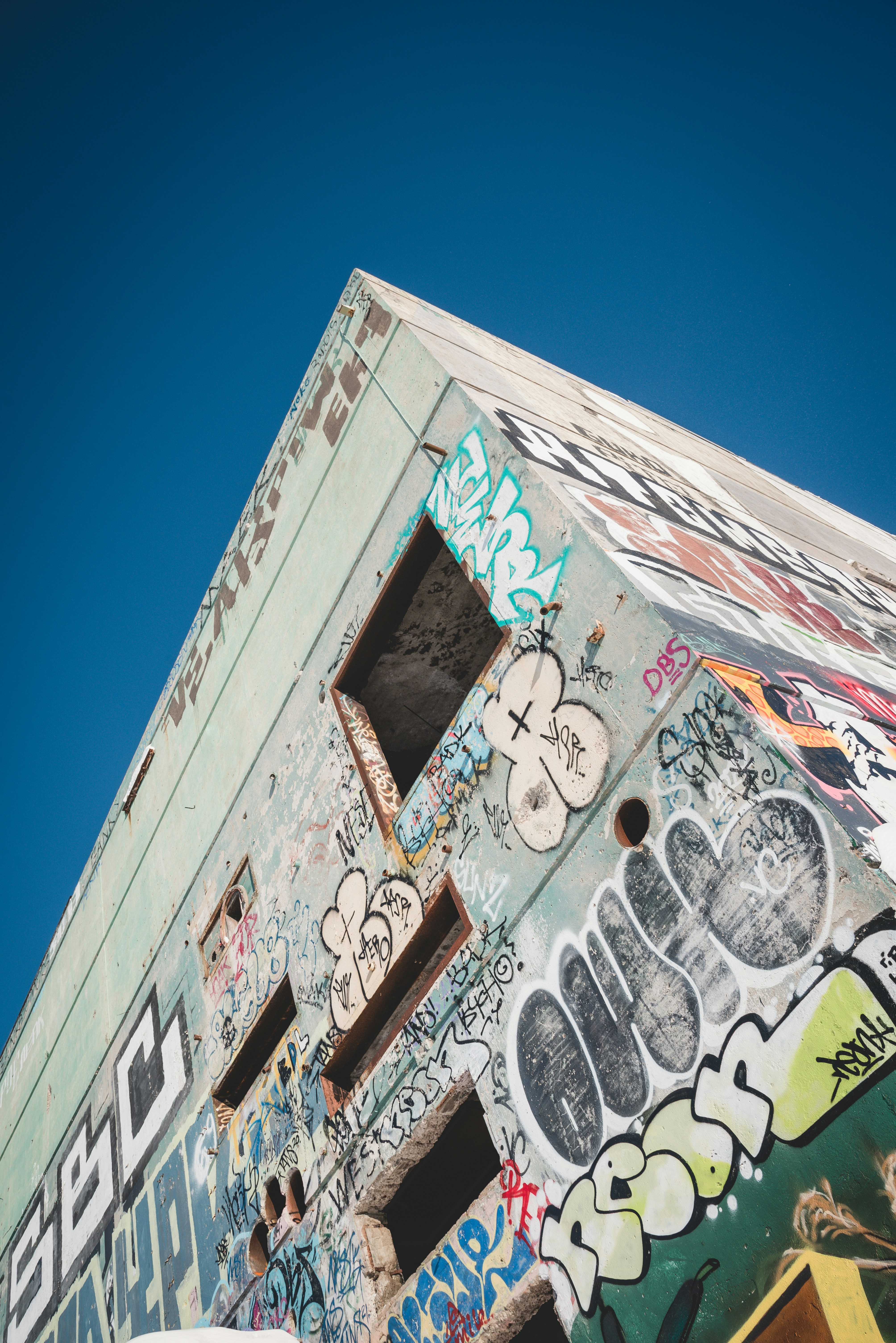 A building covered in lots of graffiti under a blue sky photo – Free ...