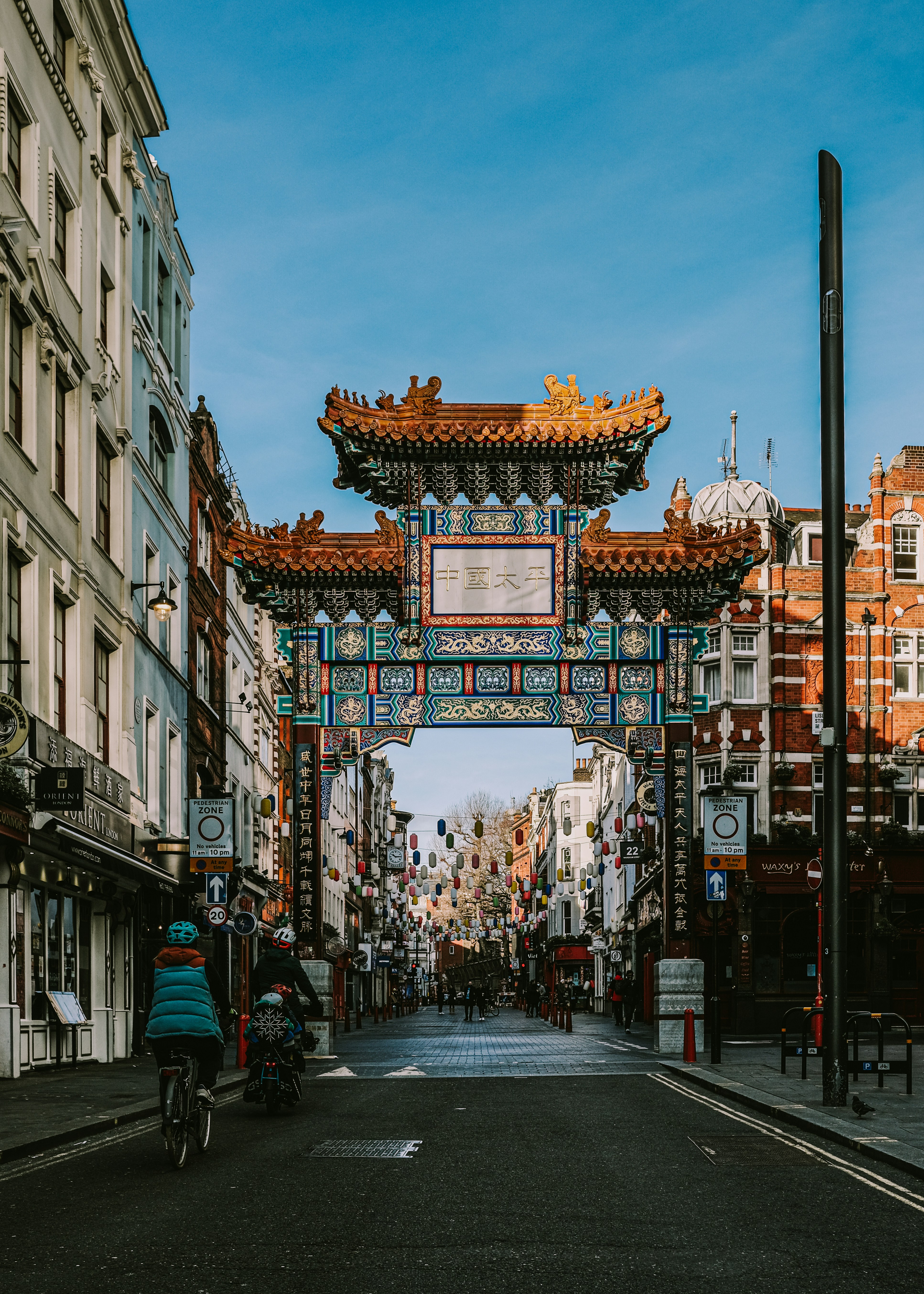 Vibrant Chinese archway adorned with intricate designs, framing a bustling street scene in Chinatown, London.