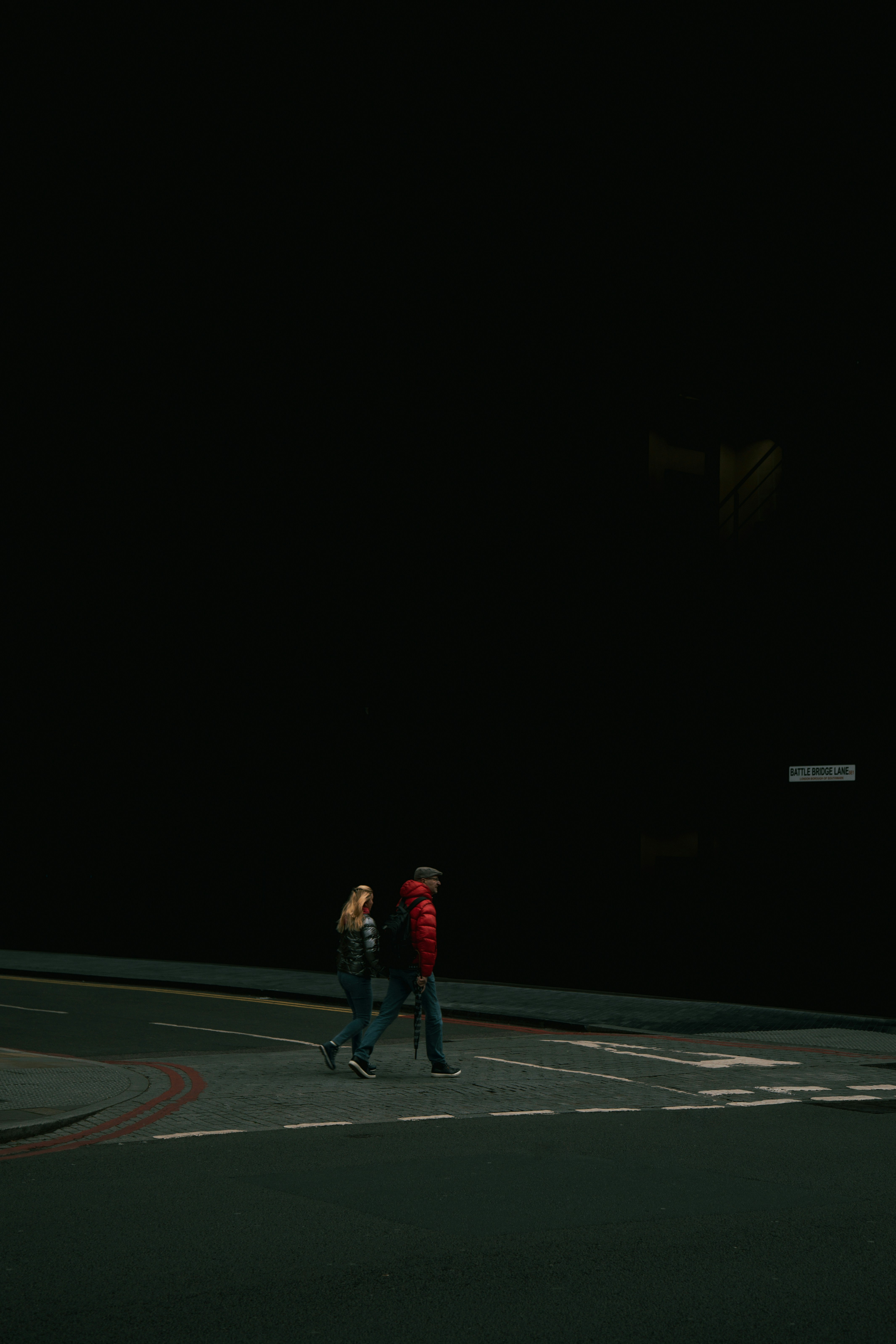 Night Crossing: Red-Jacket Duo Steps Through Quiet Urban Night