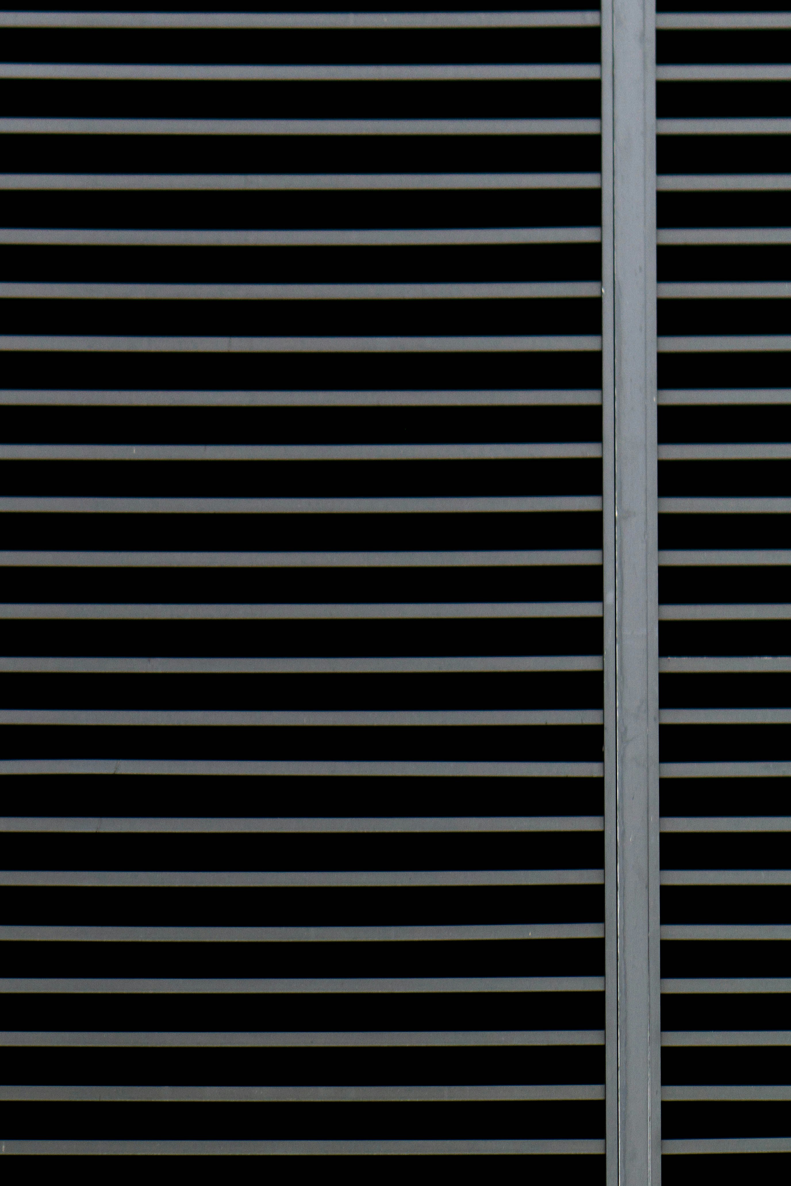 A series of horizontal lines creating a minimalist pattern against a dark background. The design emphasizes symmetry and simplicity.