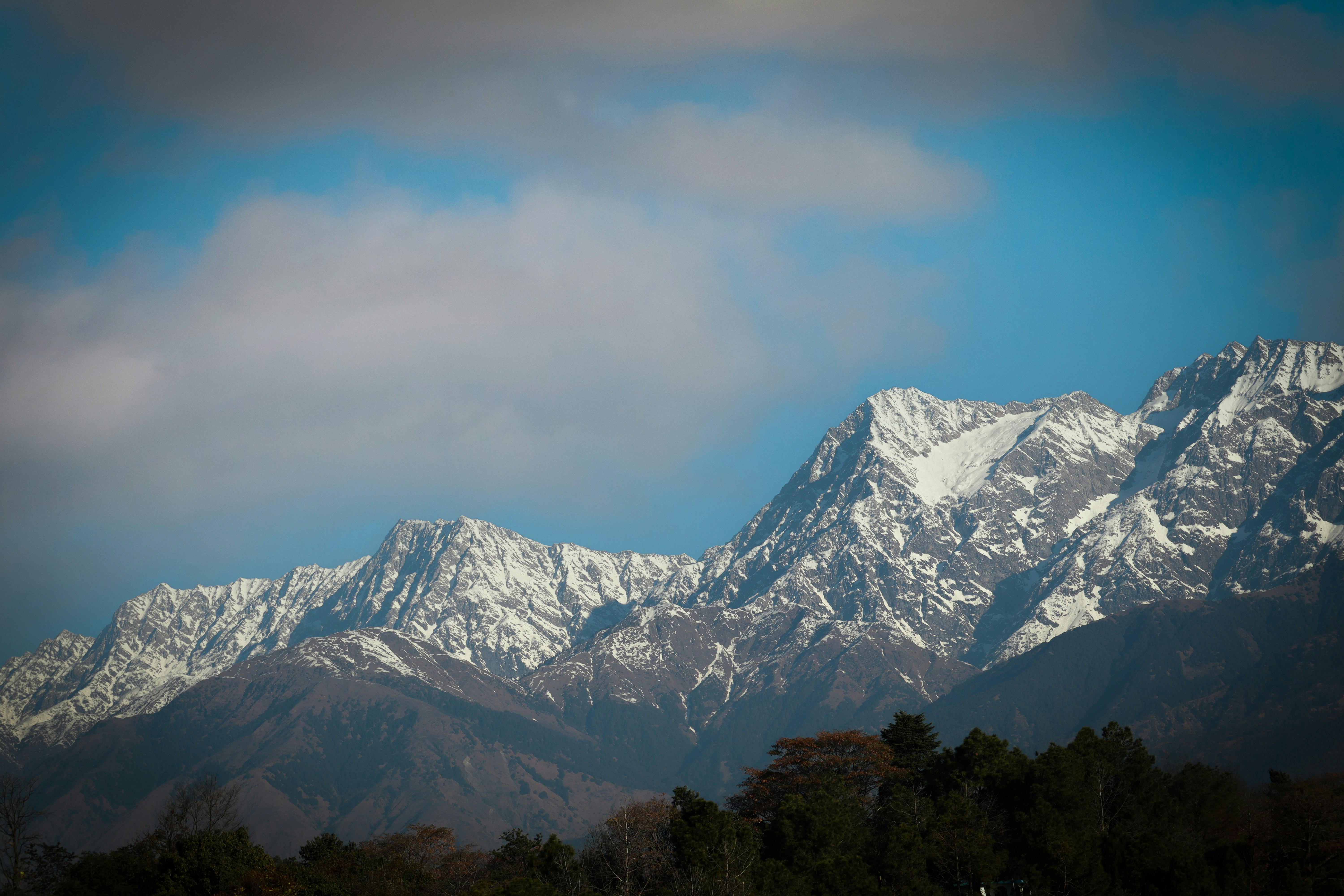 Snow-capped mountains rise against a backdrop of clear blue sky and soft clouds.