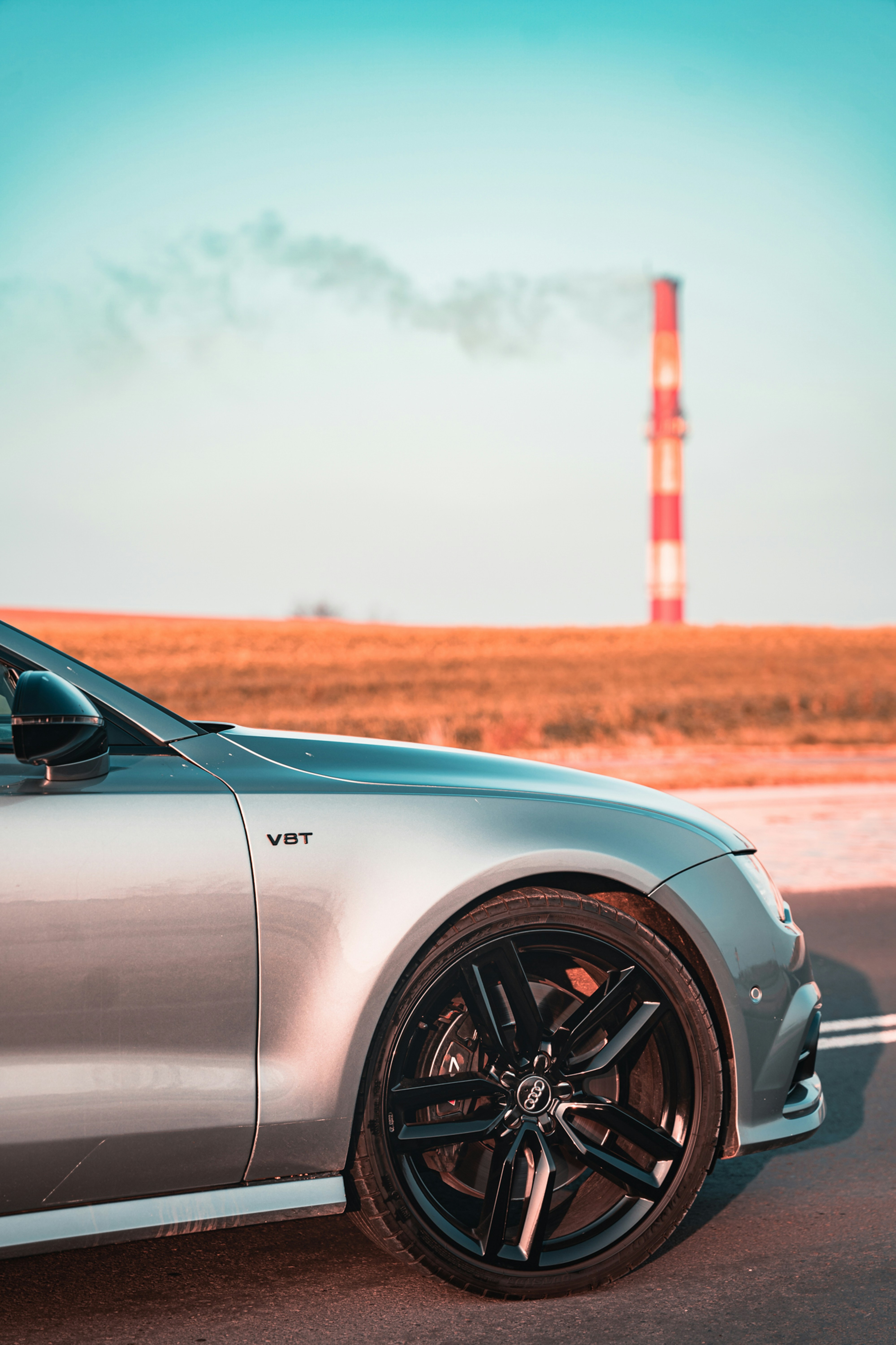 Turquoise Horizon, Chrome Curves: A Silver Sedan Framing a Distant Chimney