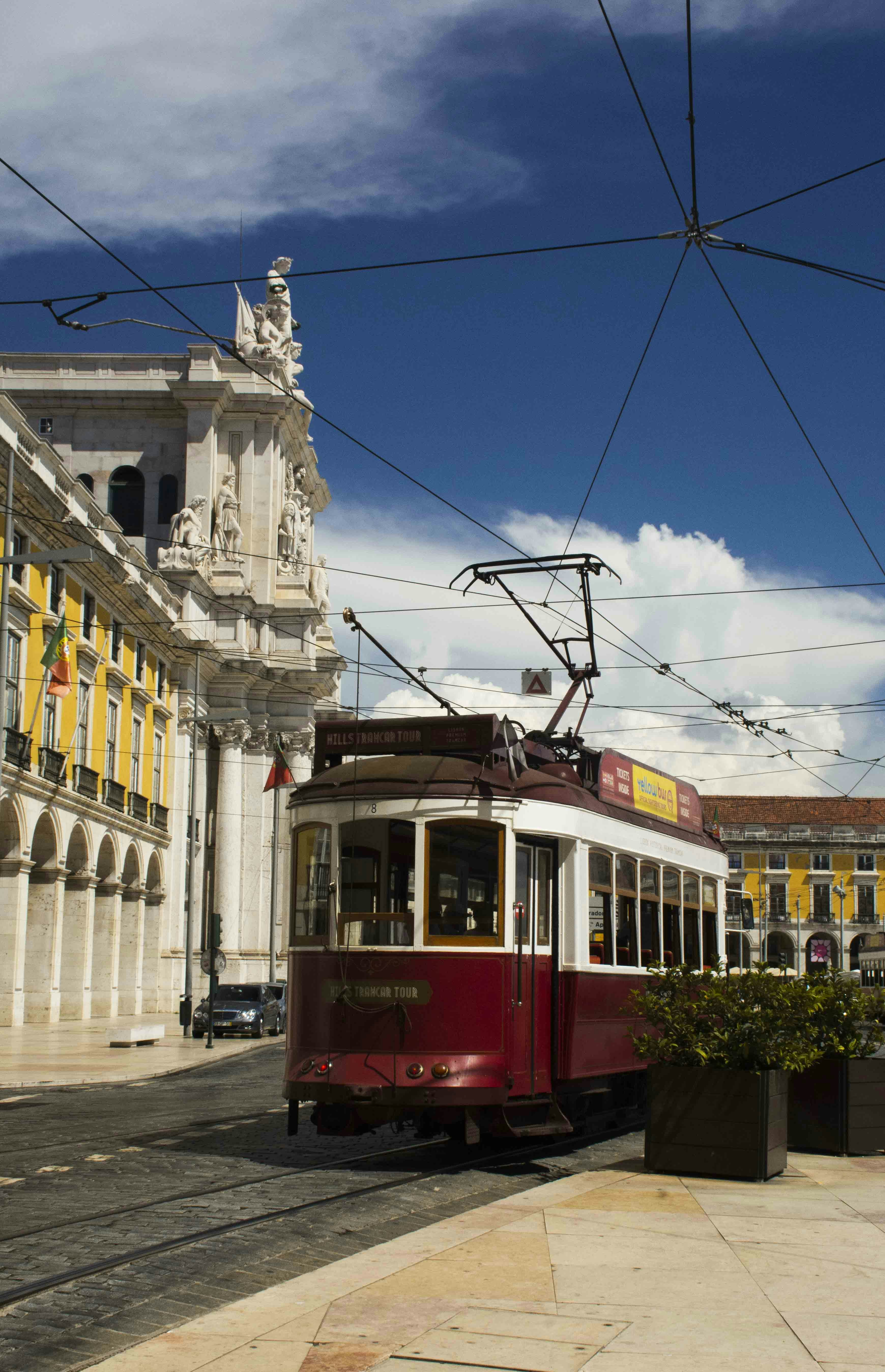 a red trolley car traveling down a street next to a tall building