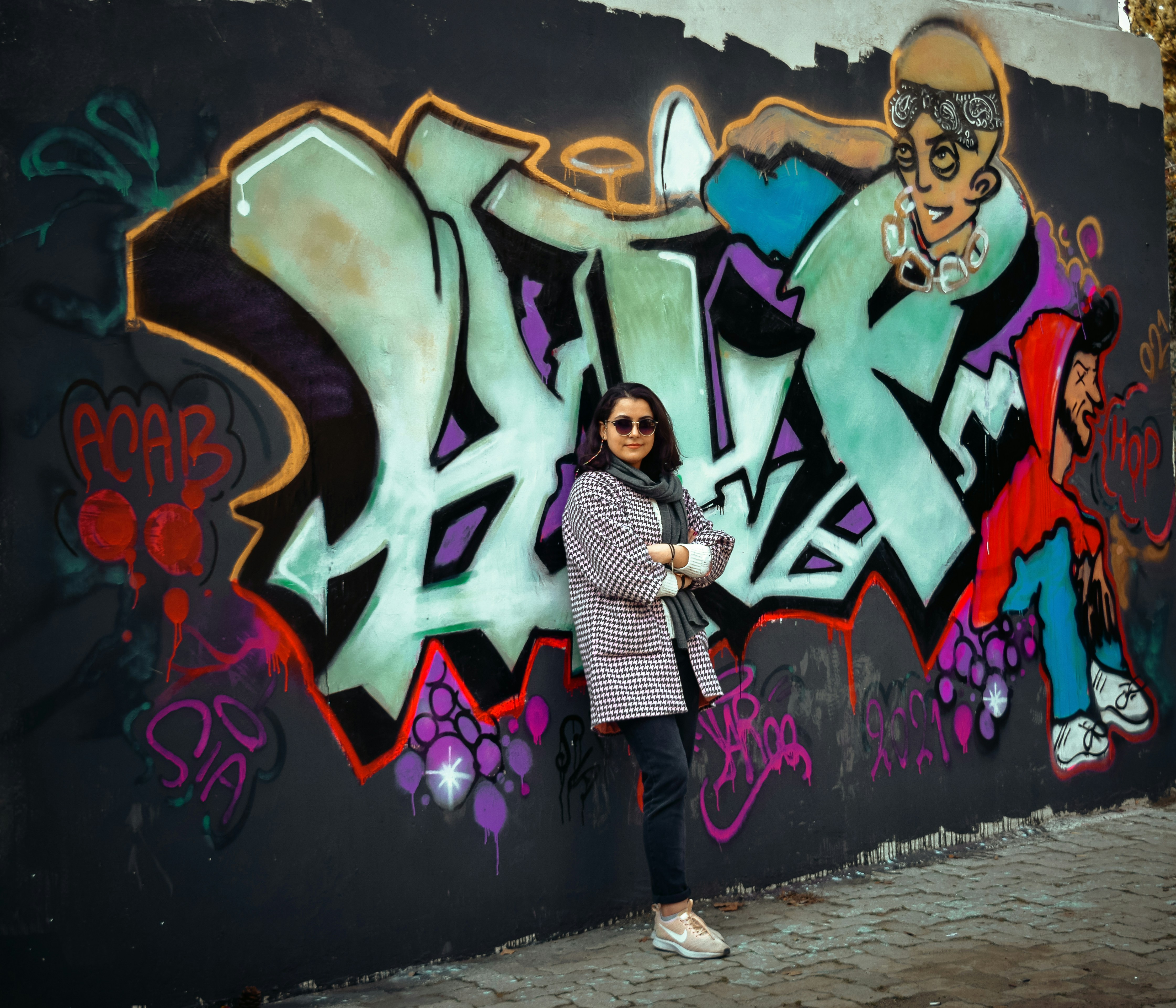 A woman standing in front of a wall covered in graffiti photo – Free ...