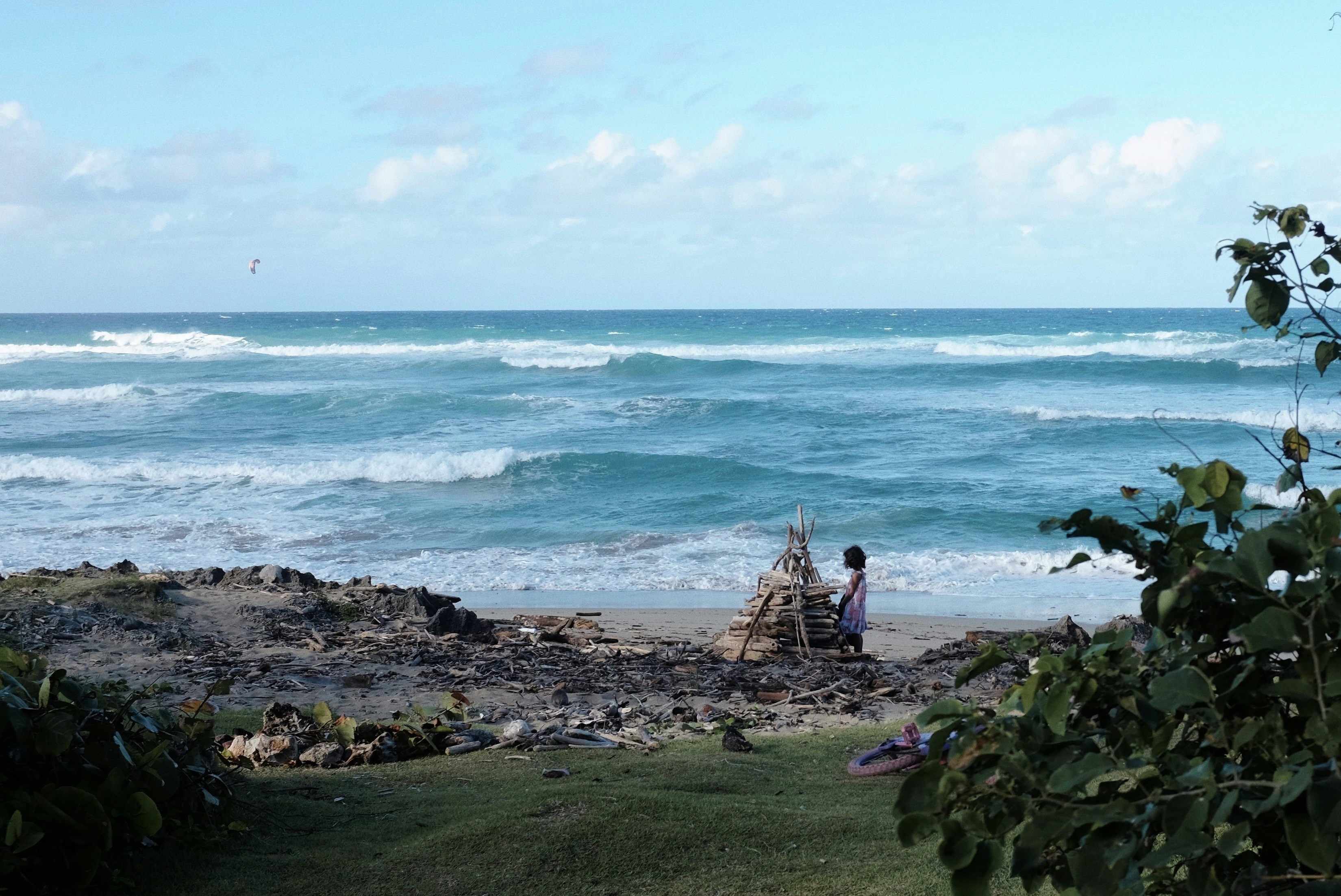 Coastal Campfire Tower: A Child Builds Amid Oceanic Light