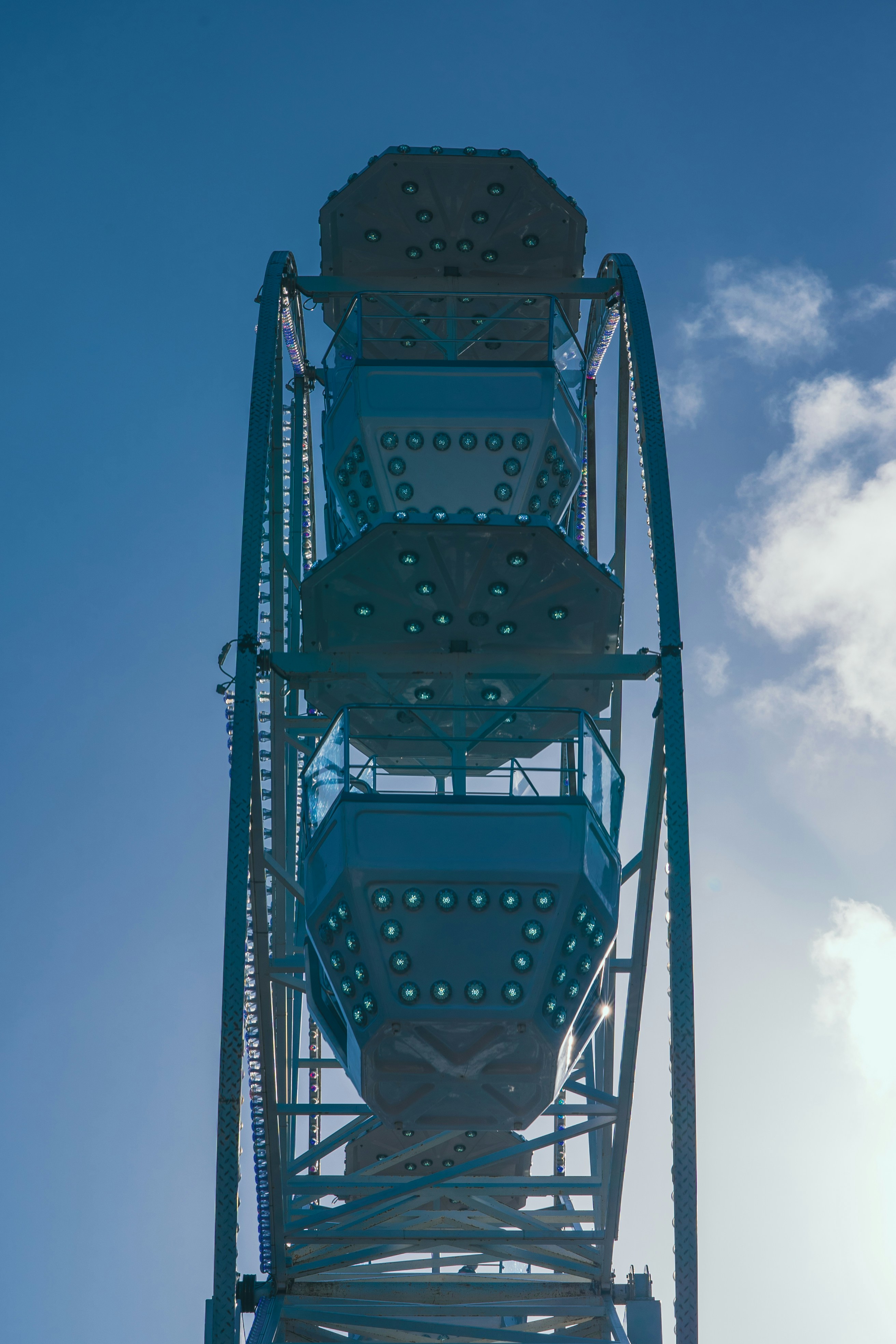 A towering Ferris wheel against a clear blue sky, showcasing its illuminated cabins and intricate structure. The image captures the essence of amusement and adventure.