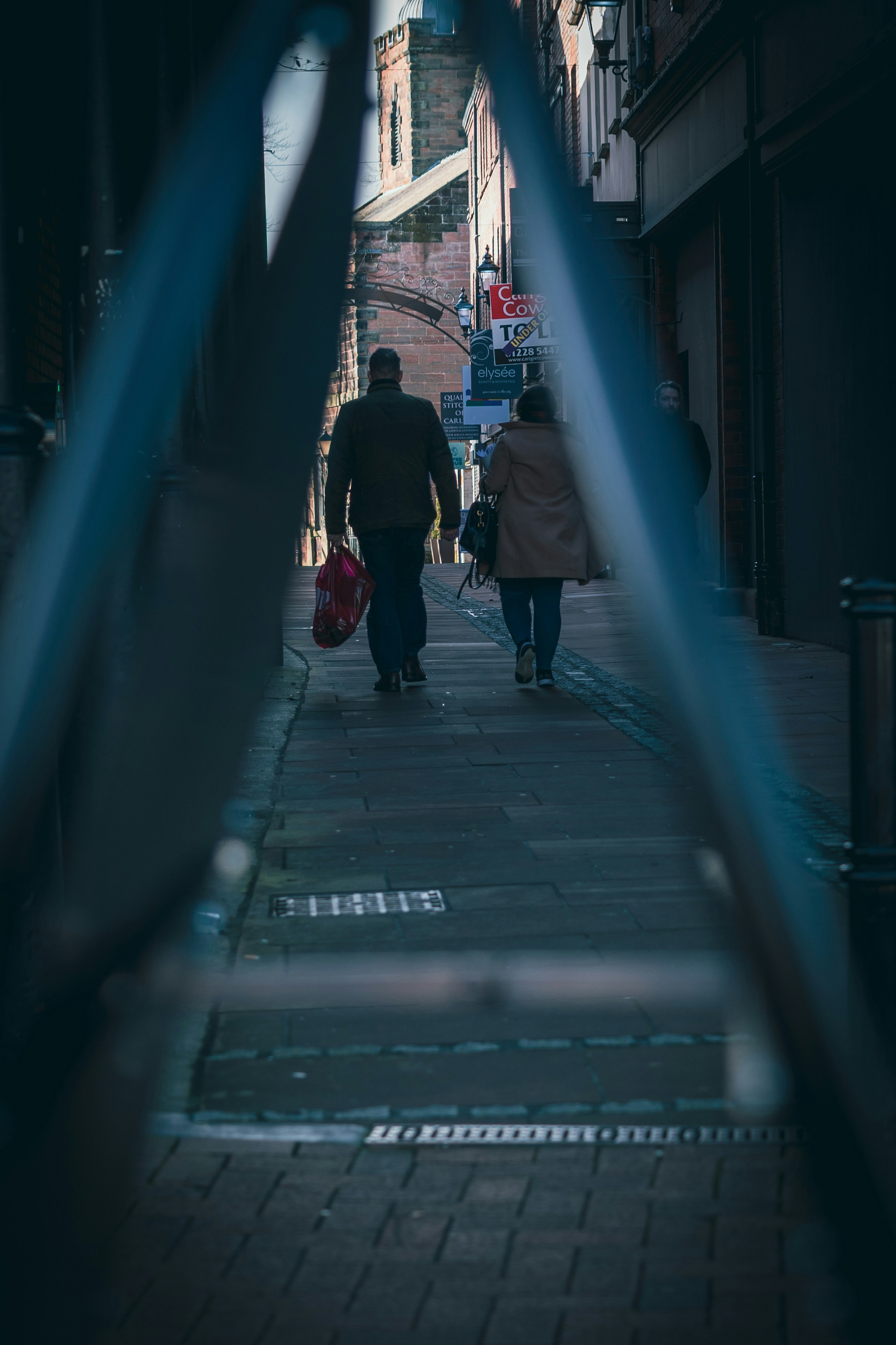 Through the Urban Rails: People Walking Through a Narrow Alley Framed by Blur