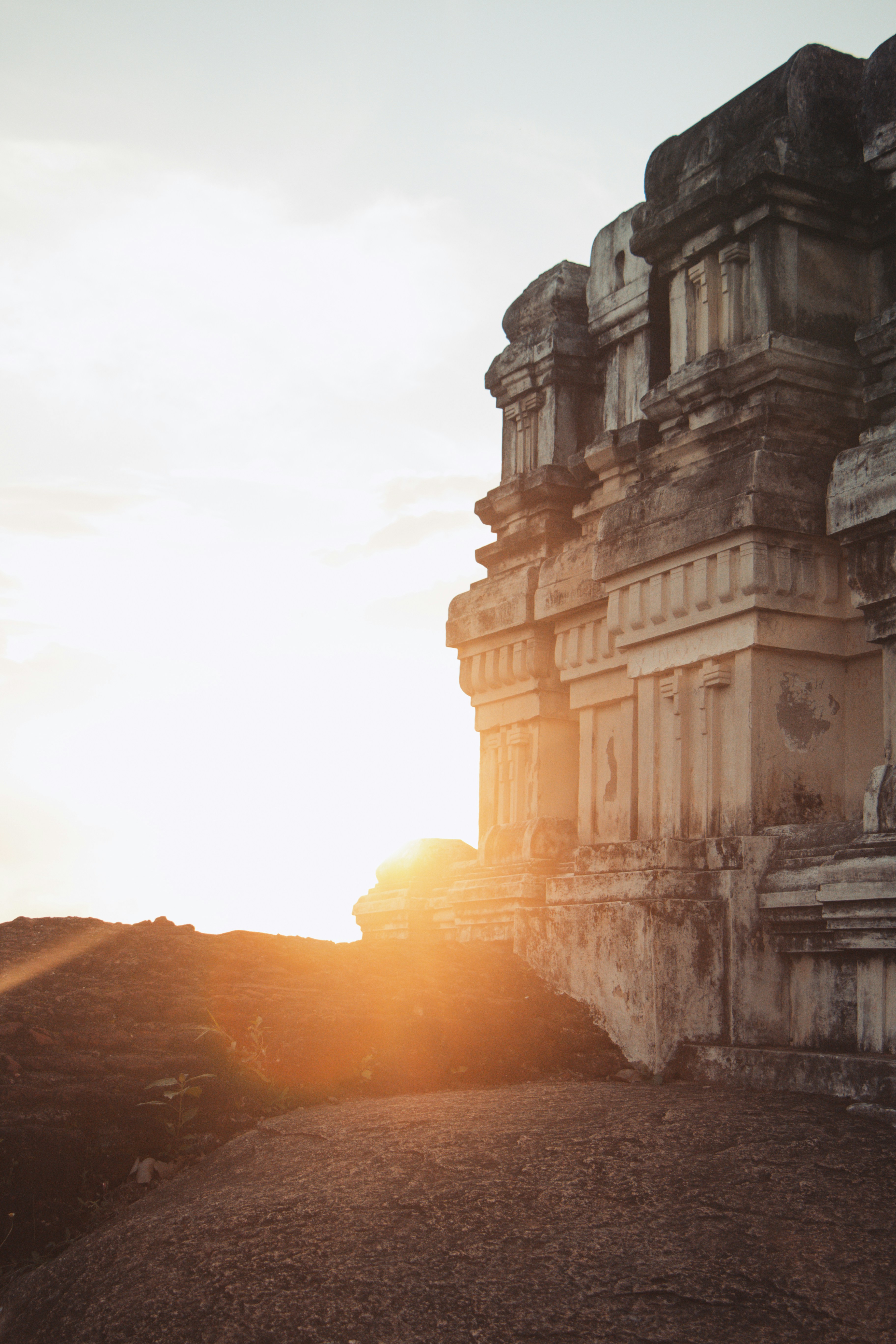 Sunset illuminates the weathered facade of ancient ruins, casting a warm glow.