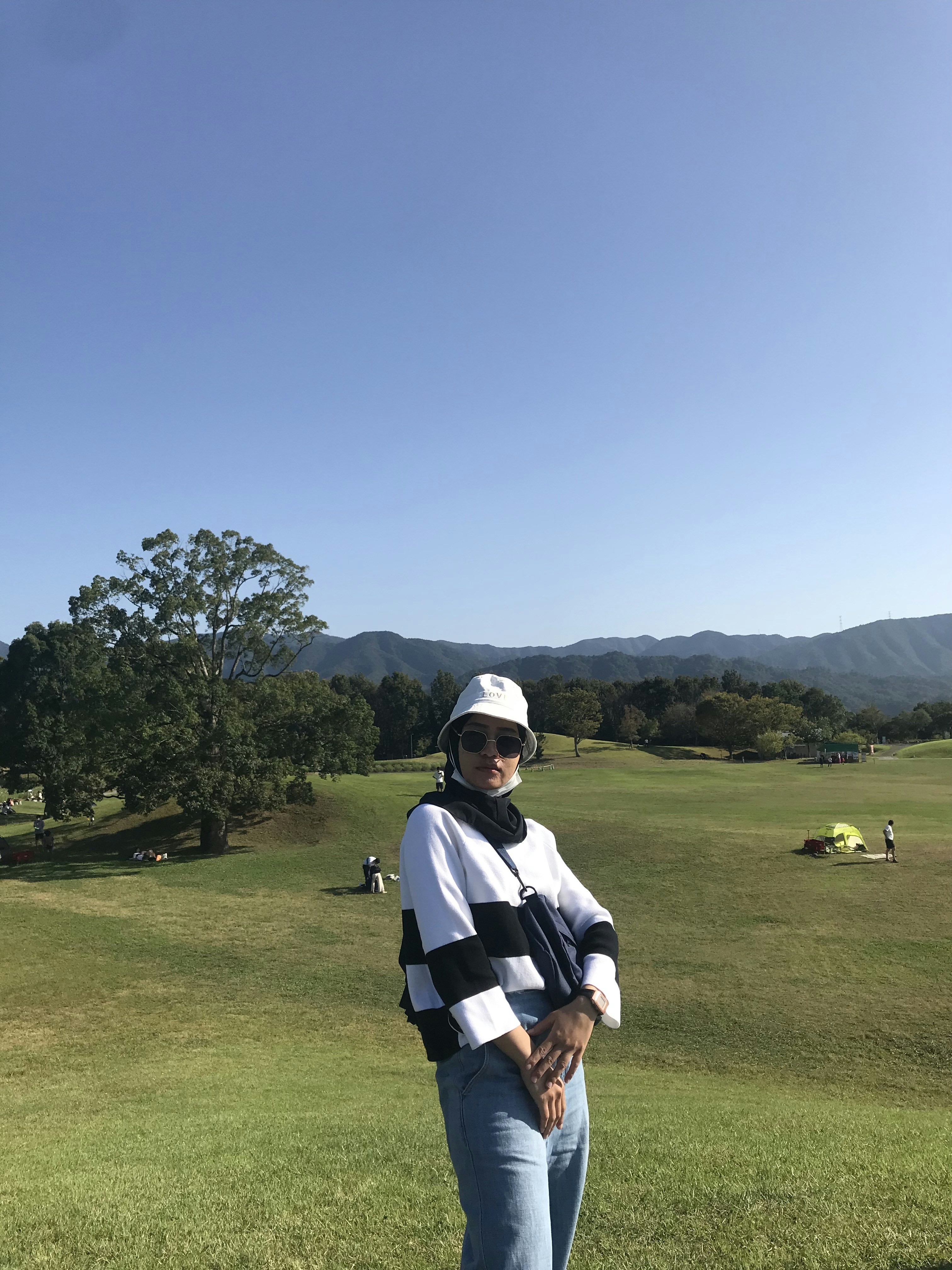 Parkside Confidence: Casual Portrait Beneath a Clear Sky and Mountain Horizon