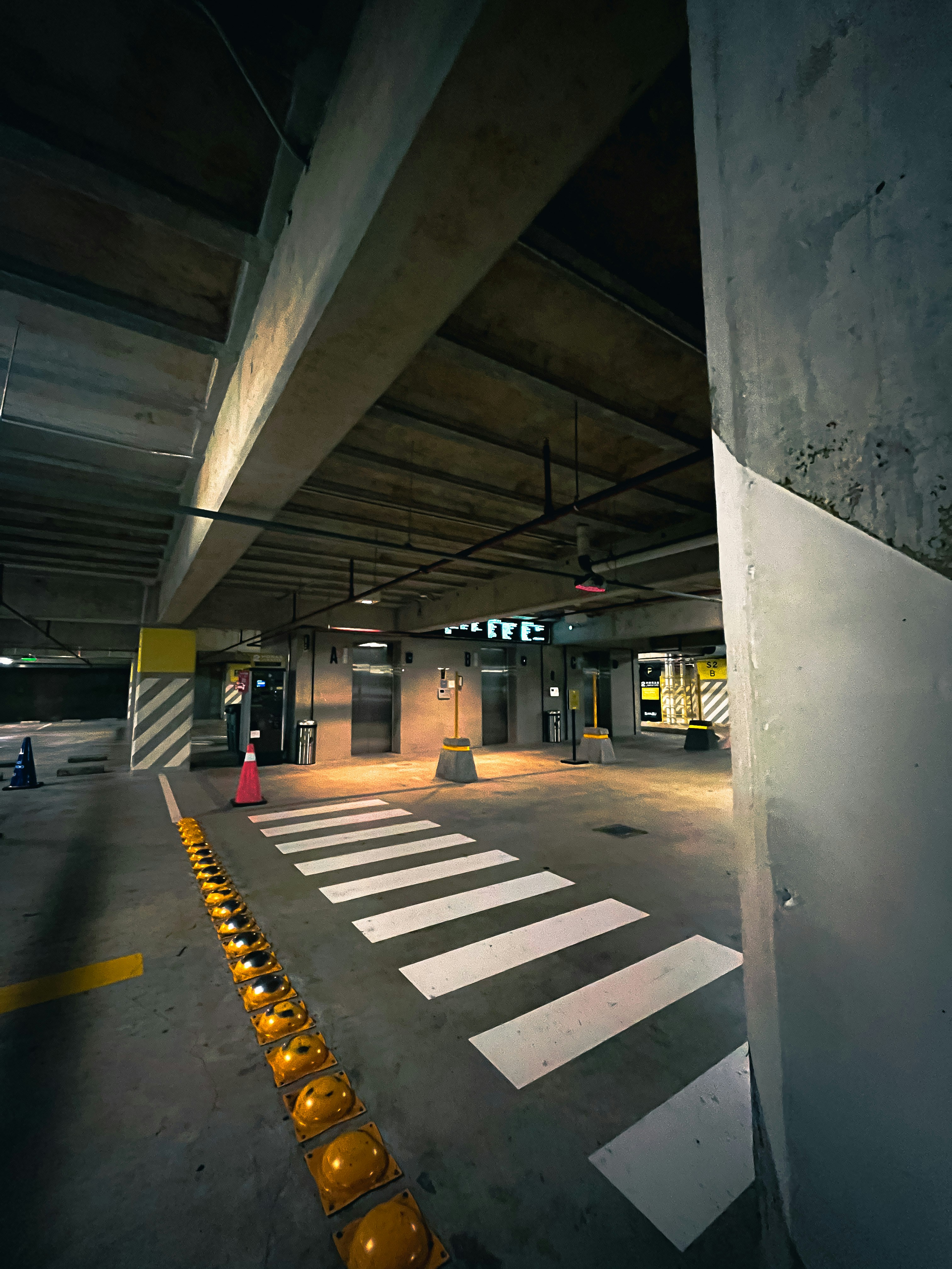 Empty parking garage showcasing concrete textures and safety features, highlighted by contrasting colors of traffic cones and floor markings.