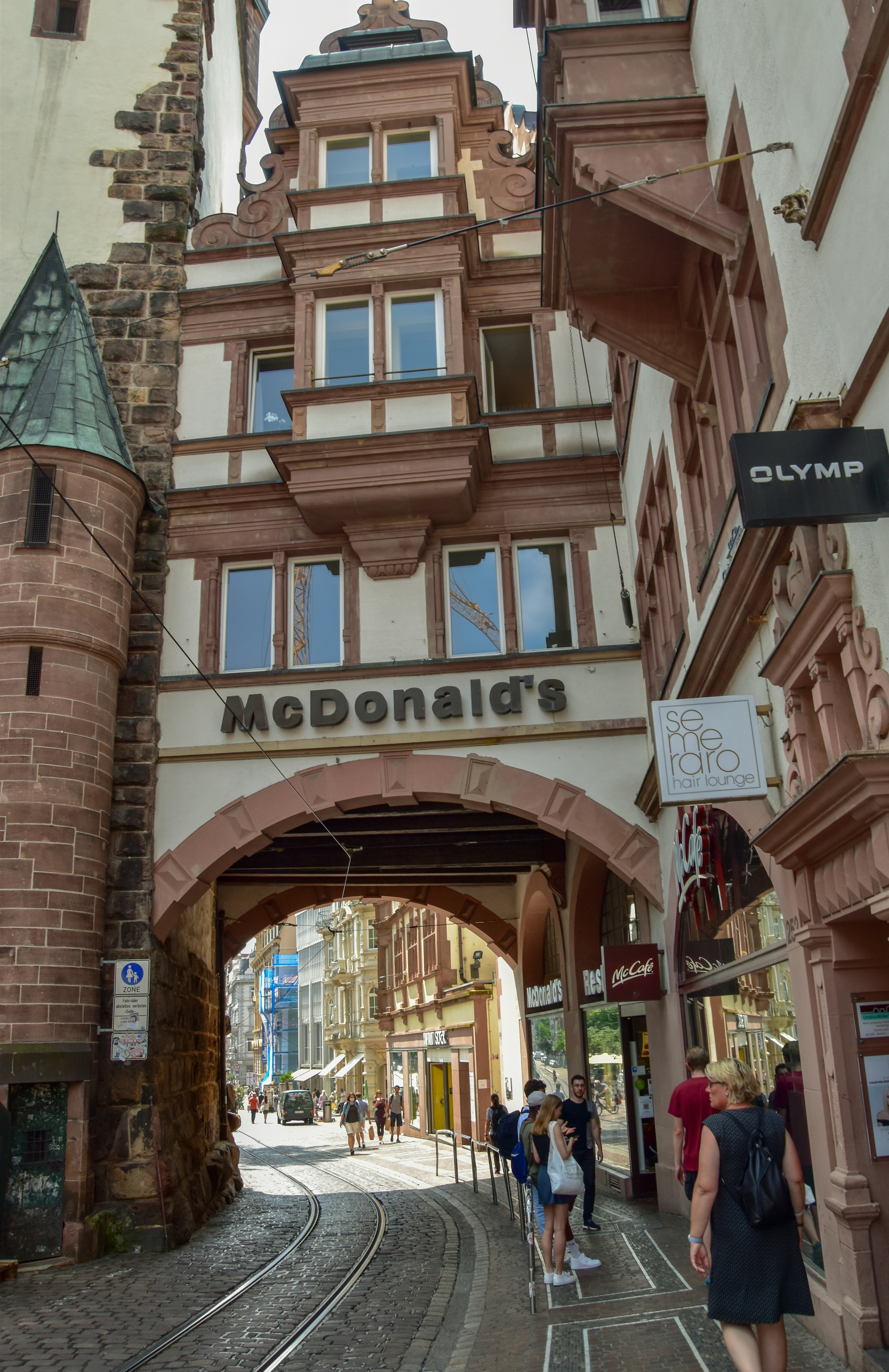Archway Corridor: A Cobblestone Street Framed by Historic Facades and a McDonald's Sign