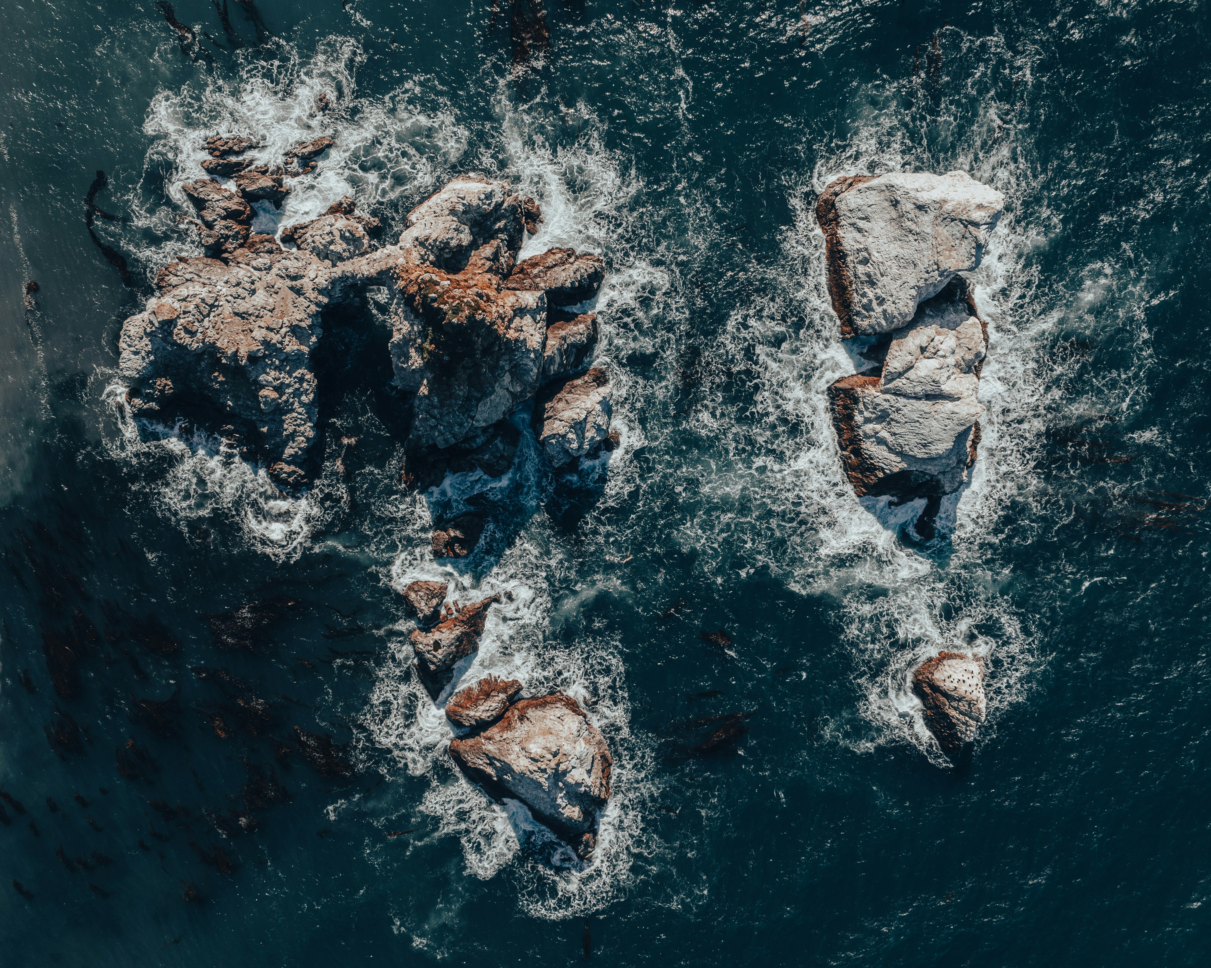 Rugged rock formations surrounded by swirling ocean waves, showcasing the dynamic interplay between land and sea.