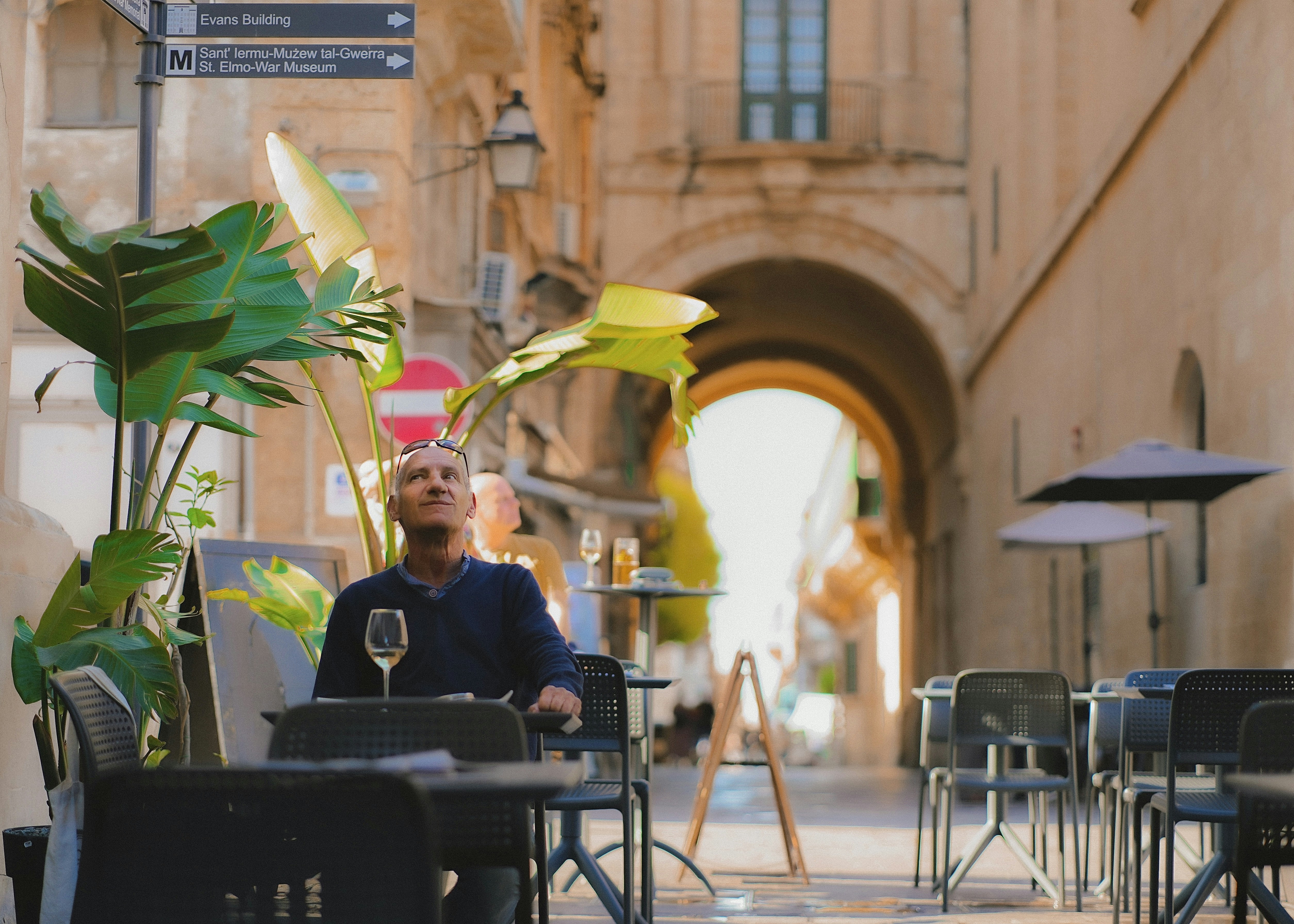 Archway Café in Sunlit Alley: A Moment Amid Green Foliage