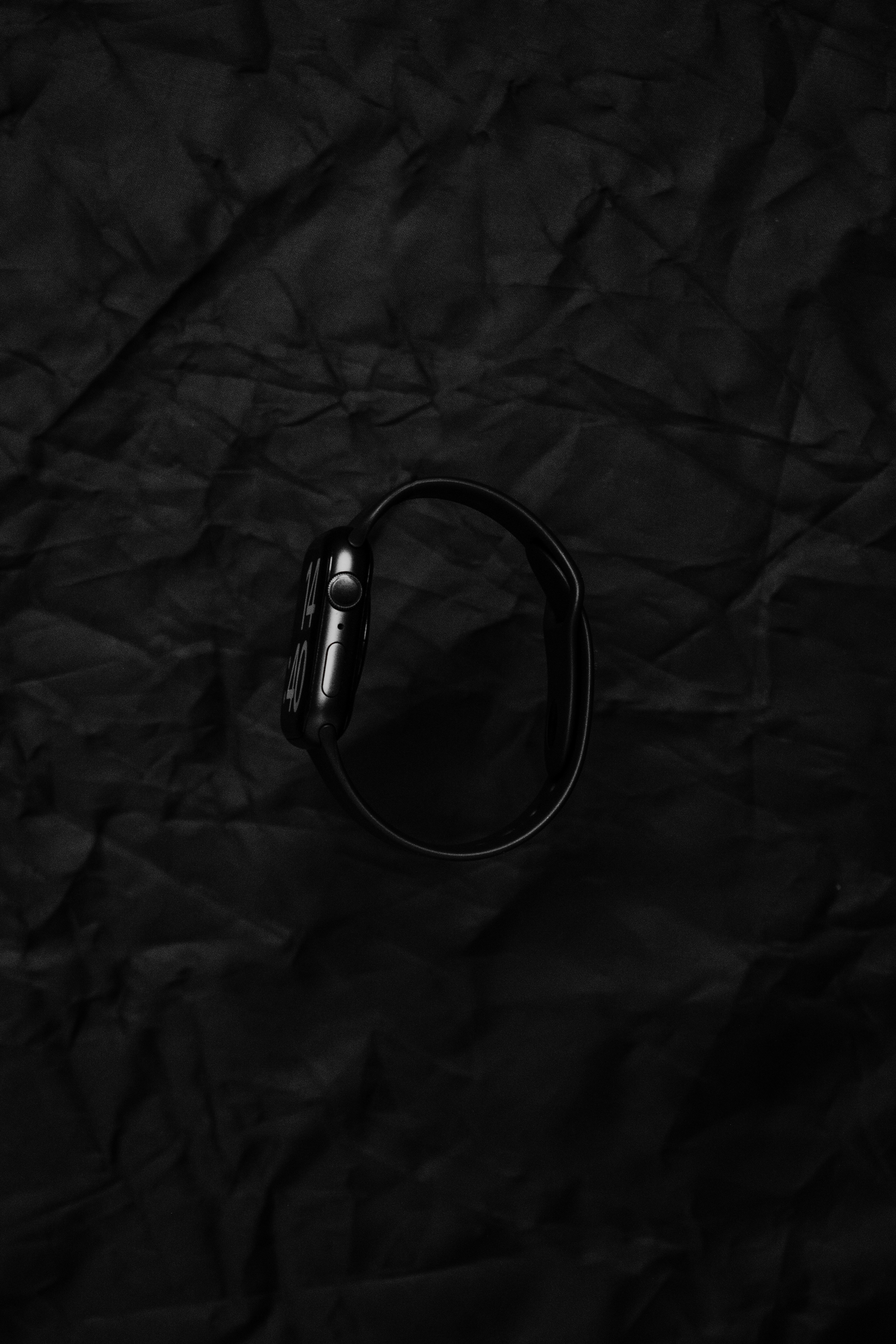 A sleek black smartwatch positioned against a textured black background, emphasizing its modern design and functionality.