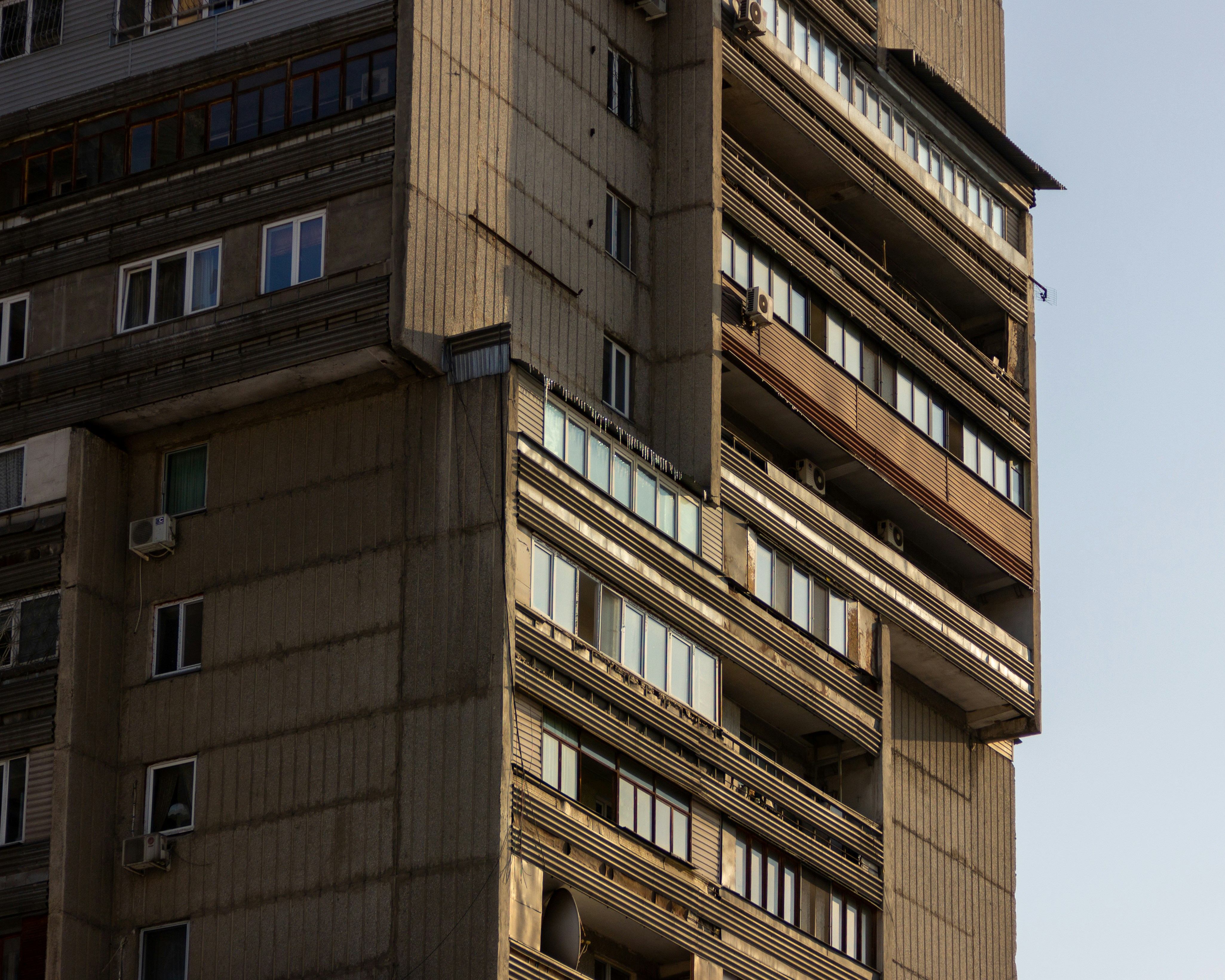 Brutalist apartment building with angular balconies catching the soft glow of sunset.