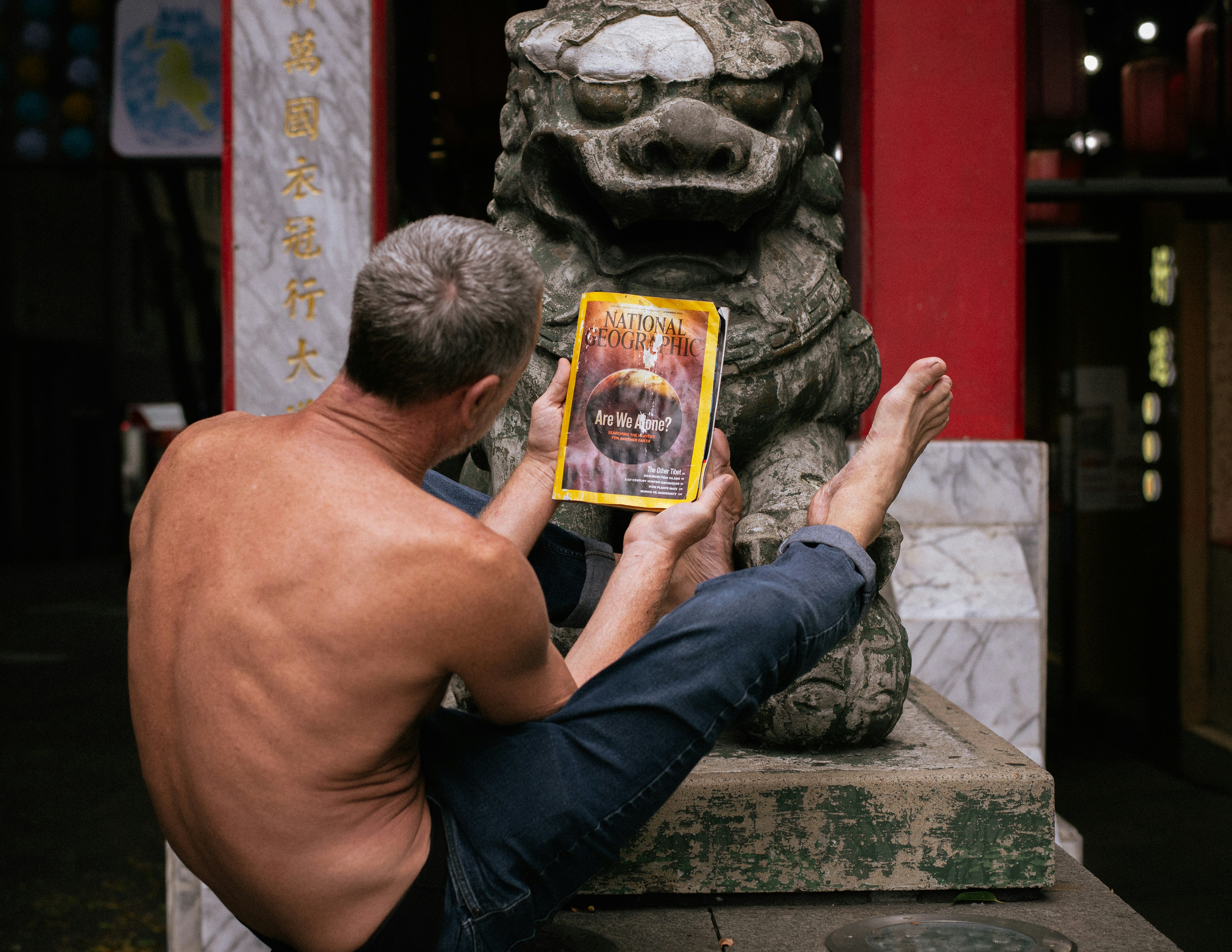 A man sitting on a stone statue reading a book photo – Free Australia ...
