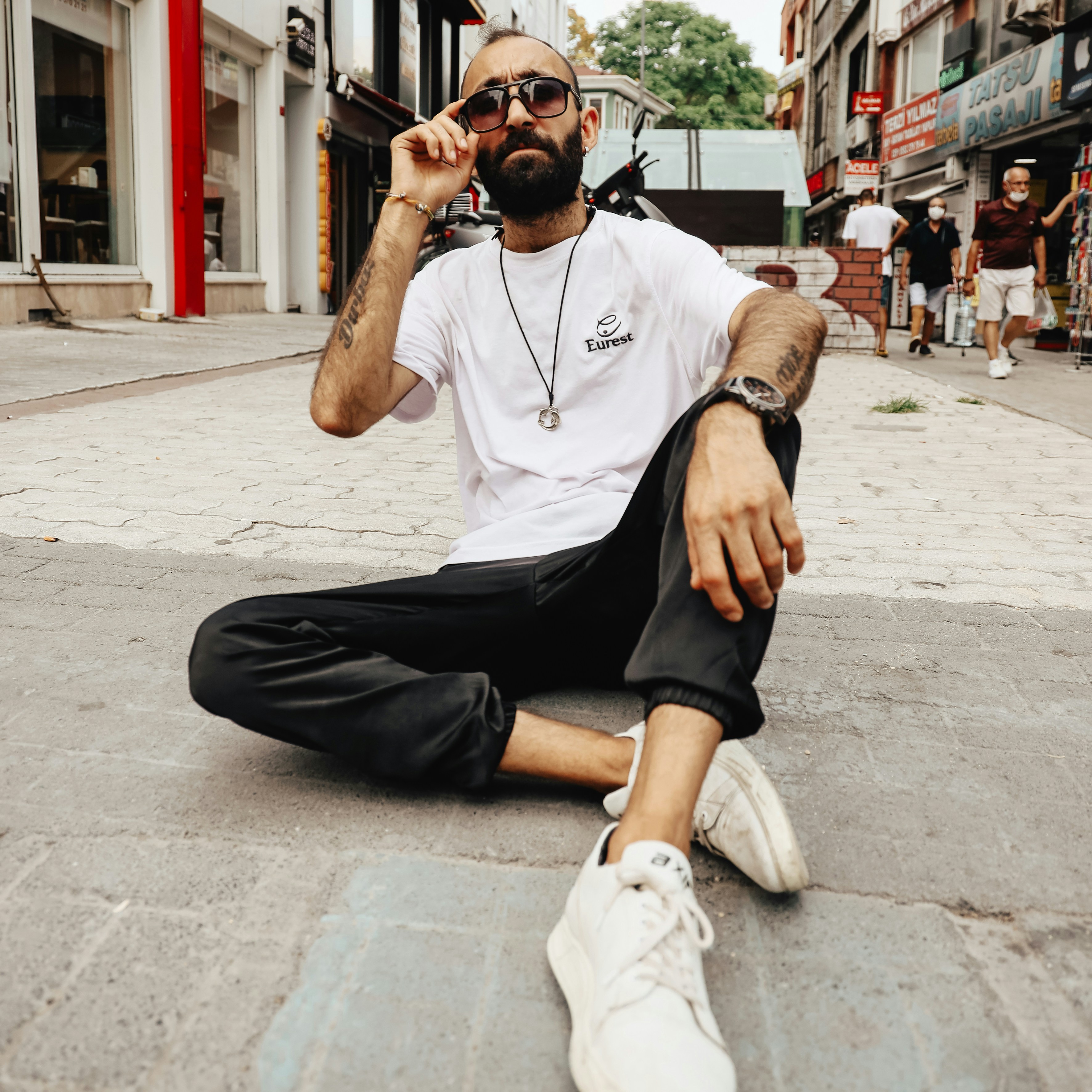 A man sitting on the ground smoking a cigarette photo – Free Person ...