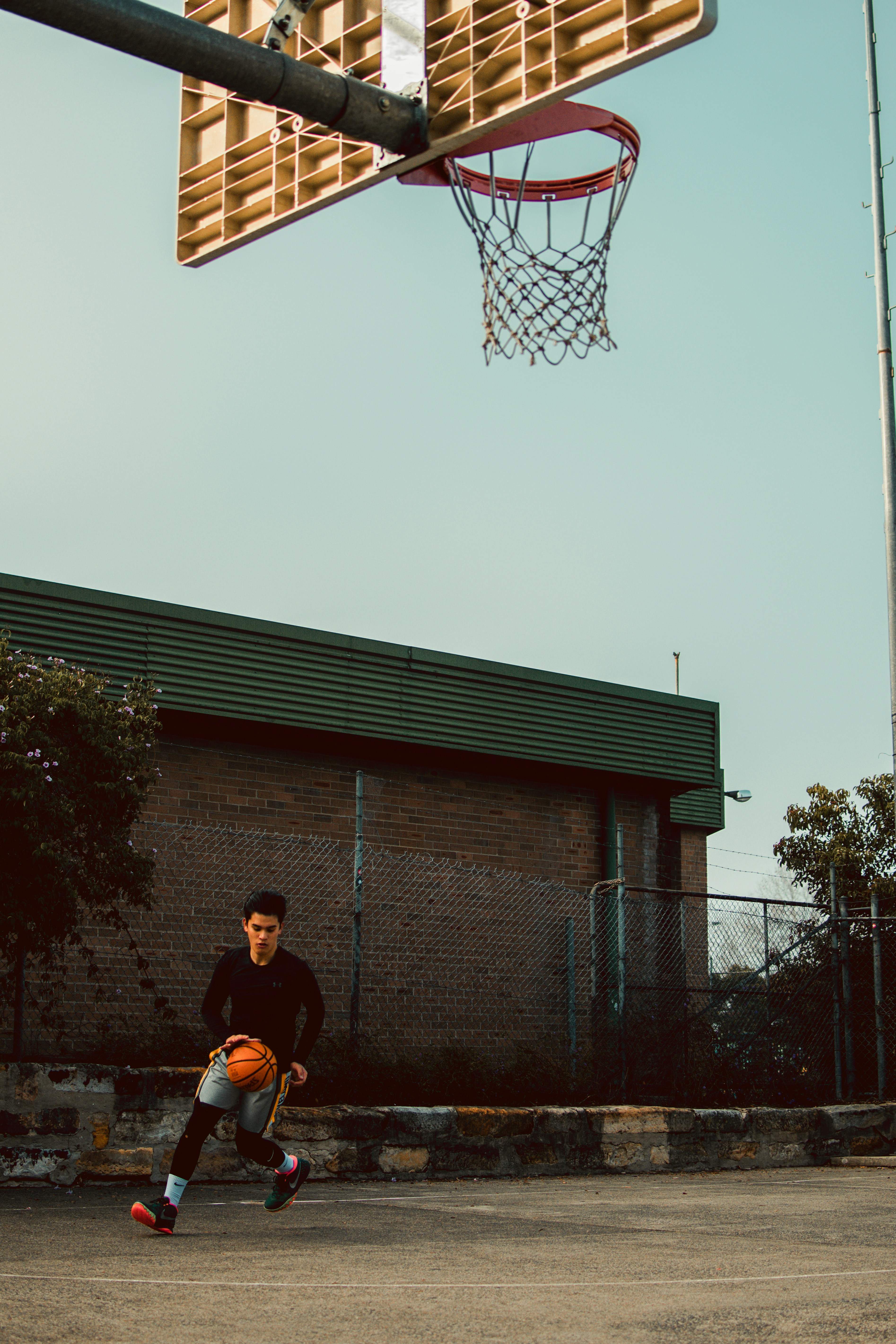 Low-angle Court: A Young Player in Motion under a Waiting Hoop