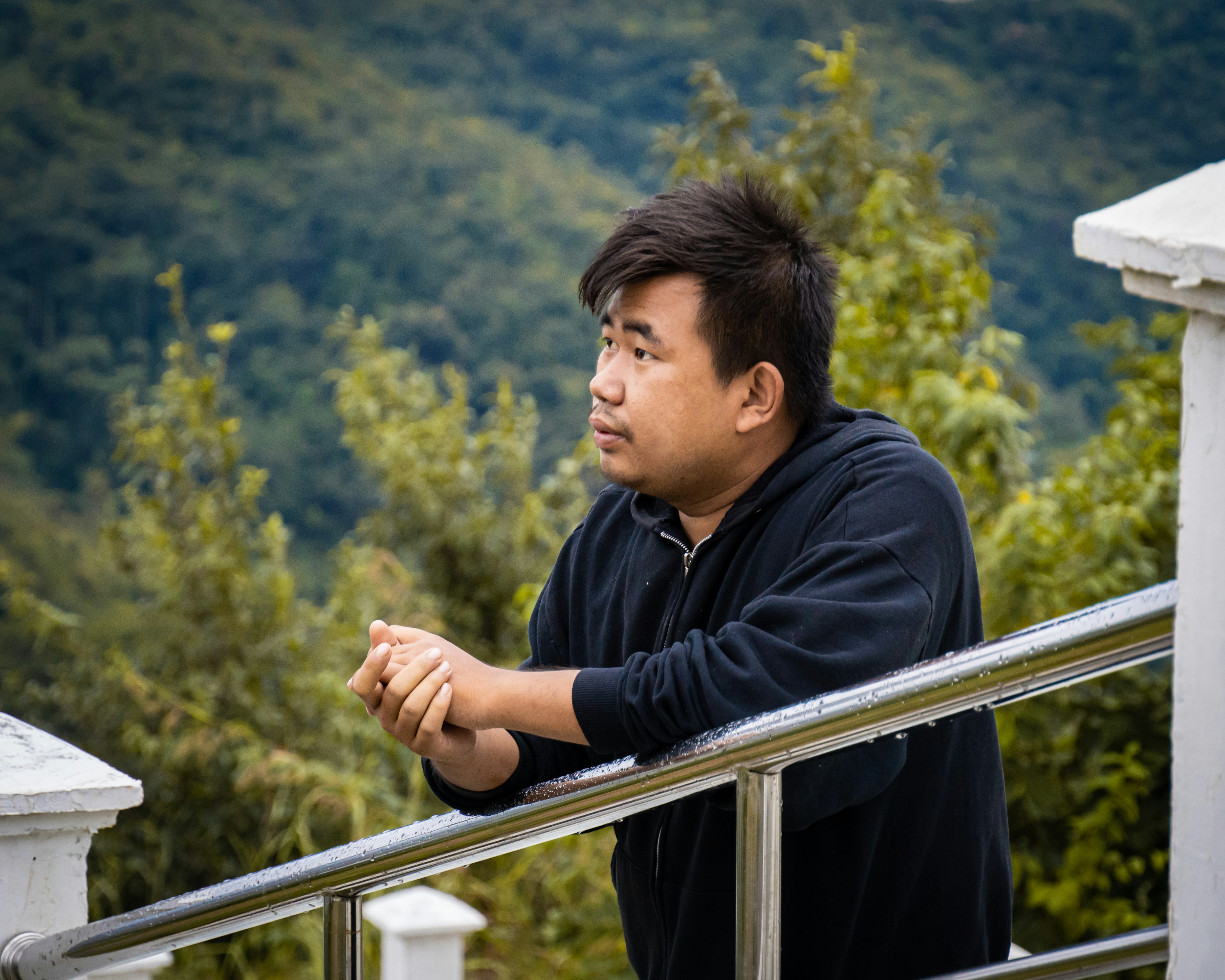 Contemplative Moment on the Balcony Rail