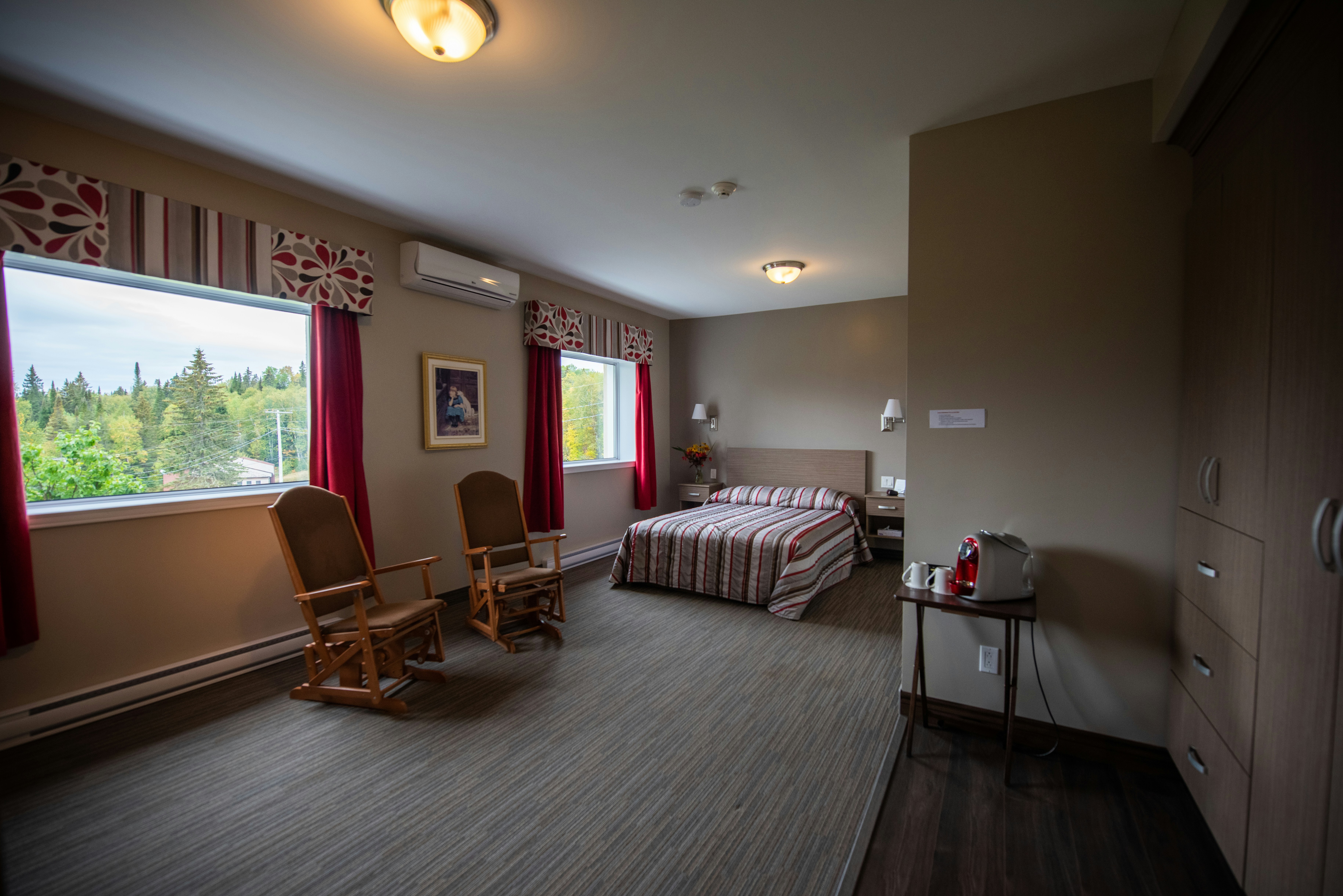 Evening Light in a Corner Hotel Room: Rocking Chairs by the Window and the Bed at the Back