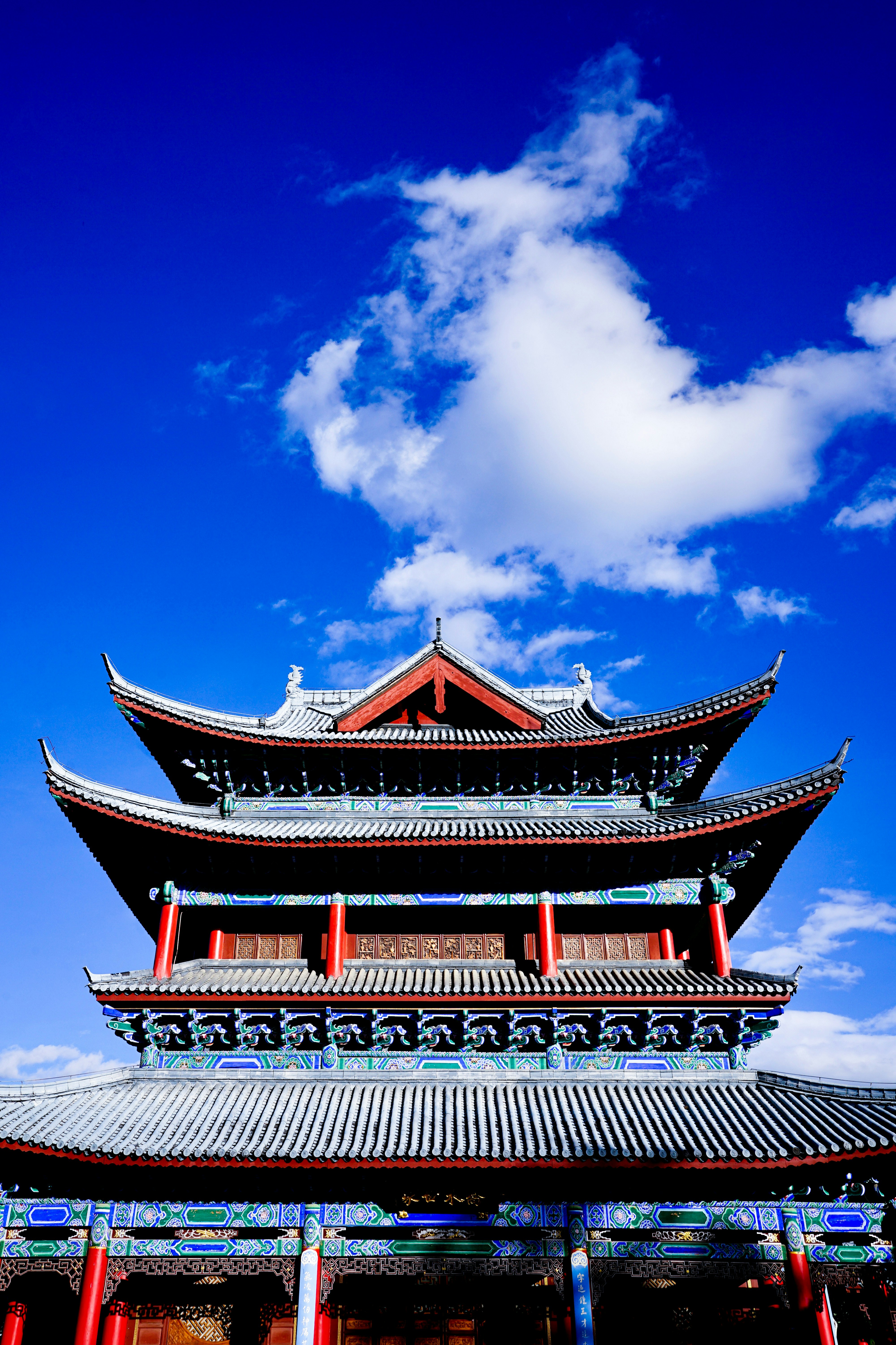 Traditional pagoda architecture with intricate details set against a vibrant blue sky adorned with fluffy clouds.