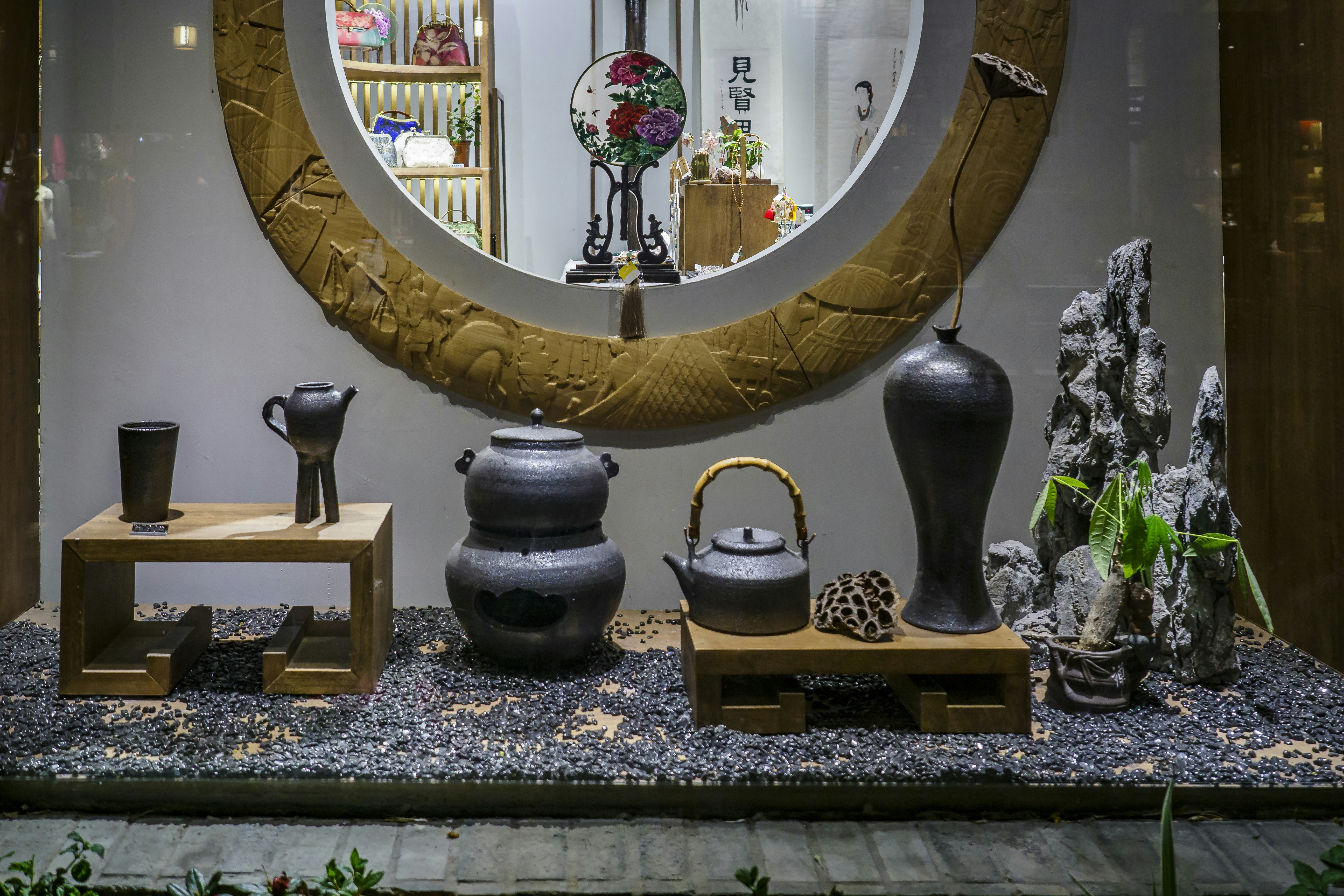 Ceramic vases and traditional teapots arranged on a textured surface within a decorative setting.