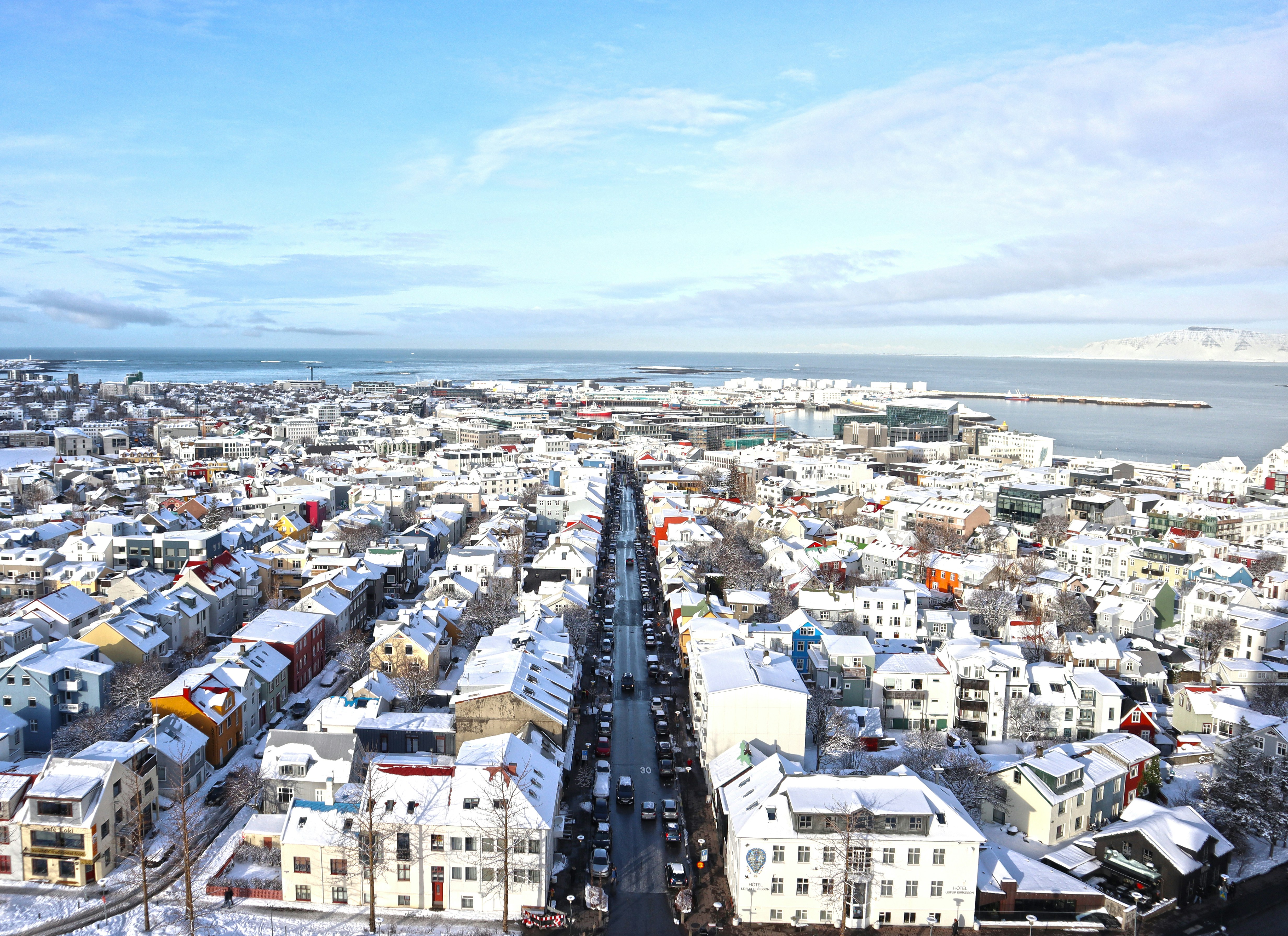A panoramic view of Reykjavik blanketed in snow, showcasing colorful rooftops and a serene harbor. The scene captures the essence of winter in the Icelandic capital.