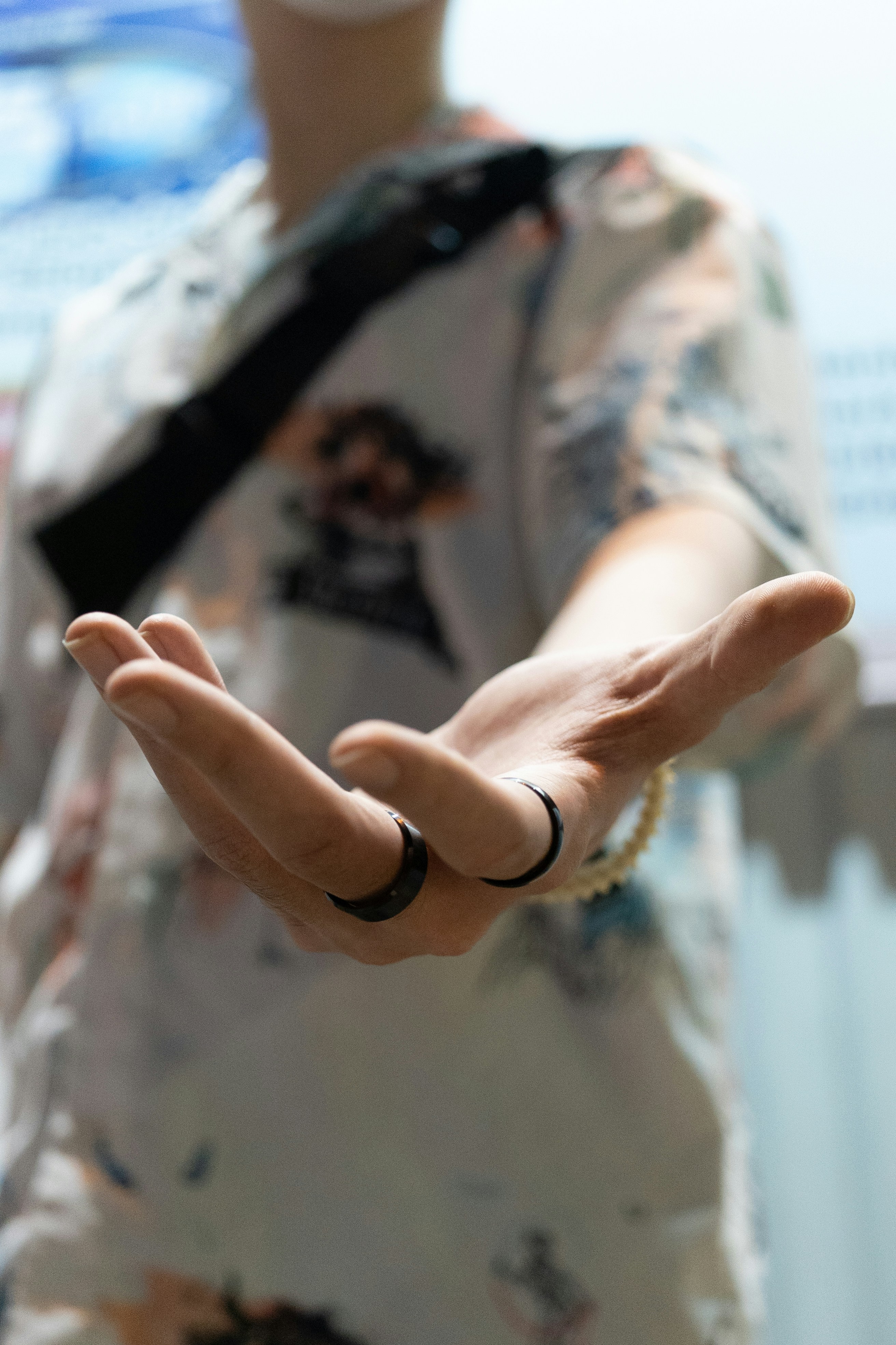 Palm Reaching Forward: A Sunlit Portrait with Soft-Blurred Floral Shirt