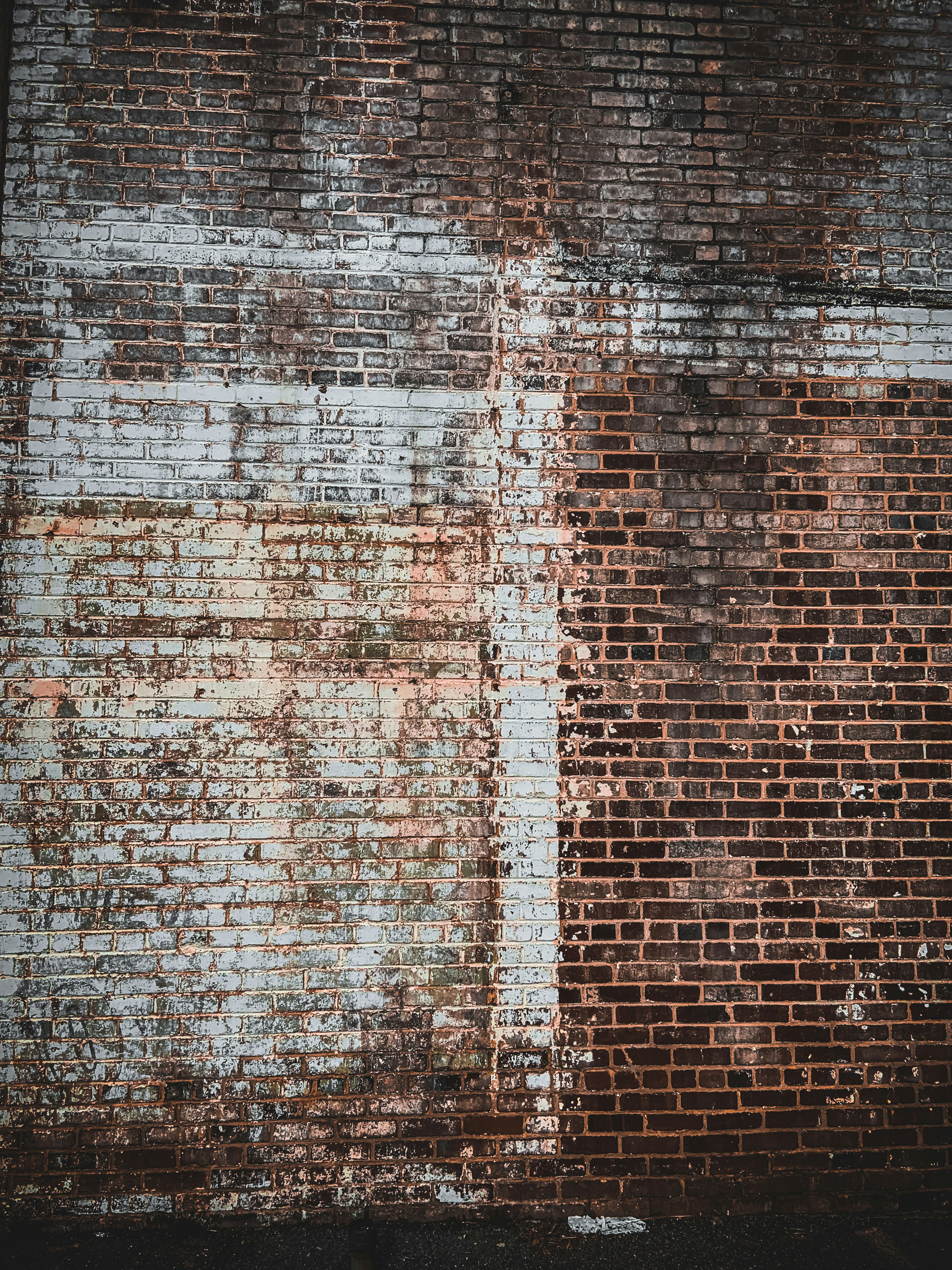Weathered brick wall showcasing layers of peeling paint and graffiti remnants, reflecting the passage of time.