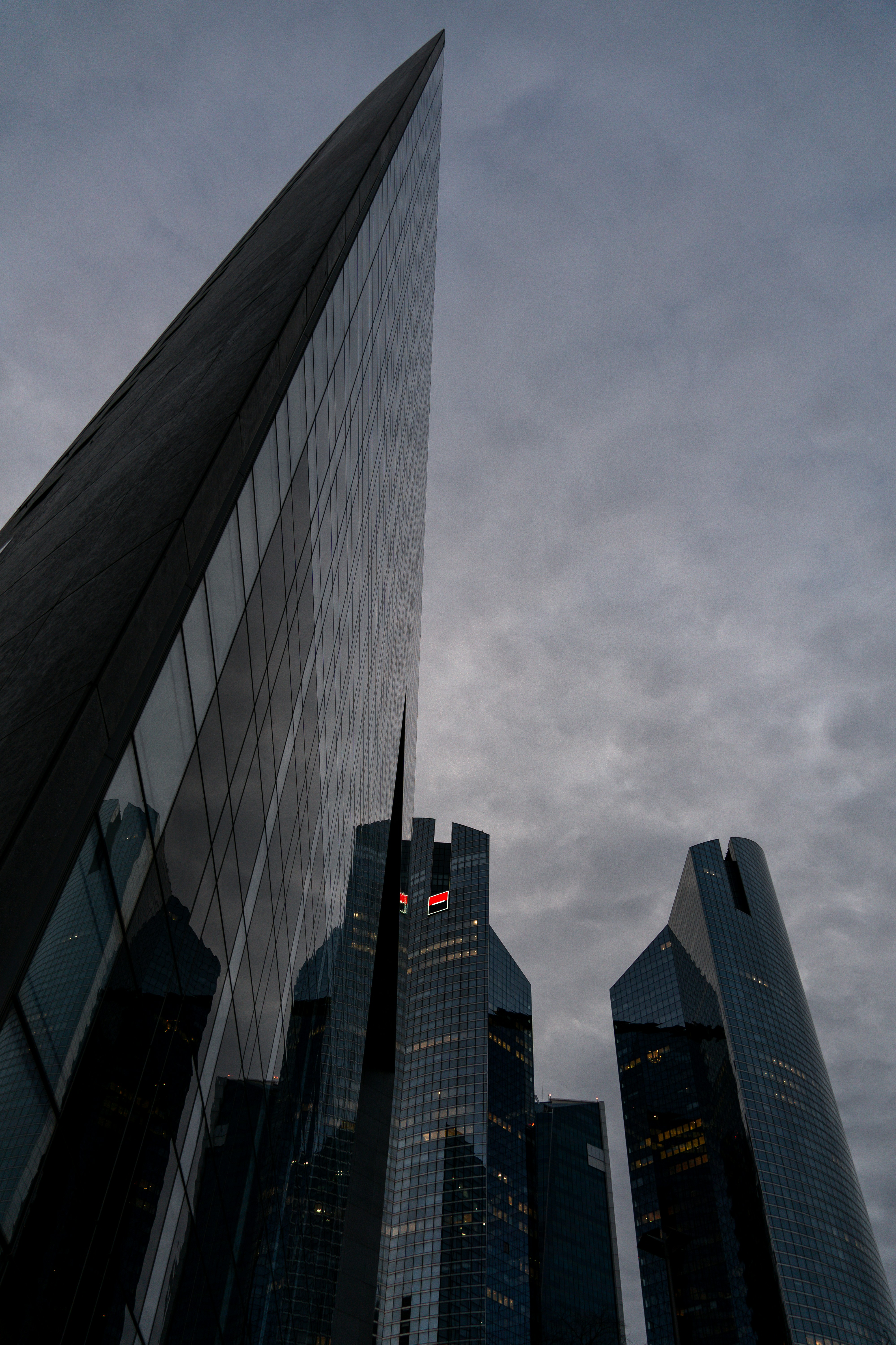 Tilted Glass Monolith Reaching Toward a Cloudy Sky