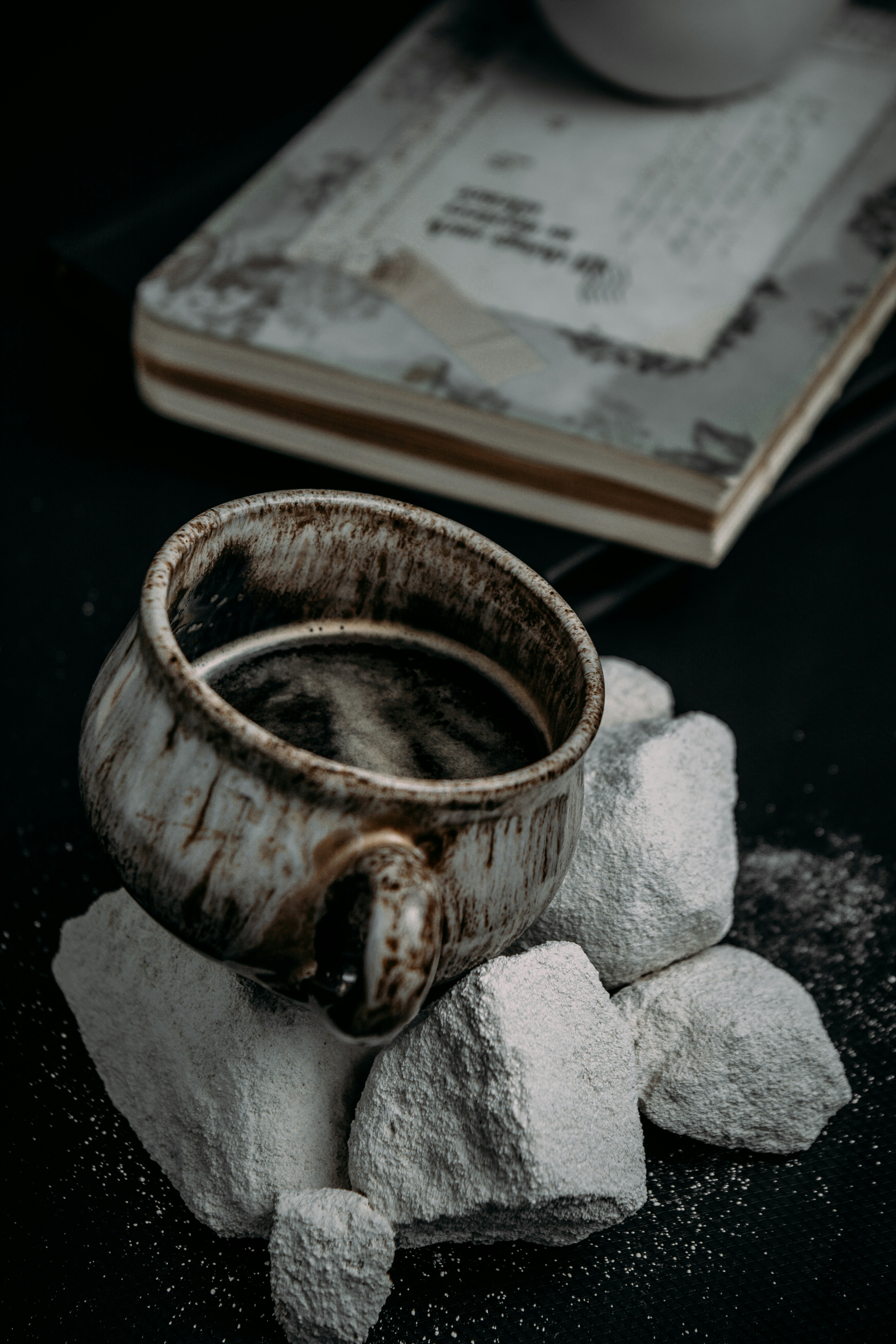 Steam meets sugar: a ceramic mug resting atop powdered rocks with a distant notebook