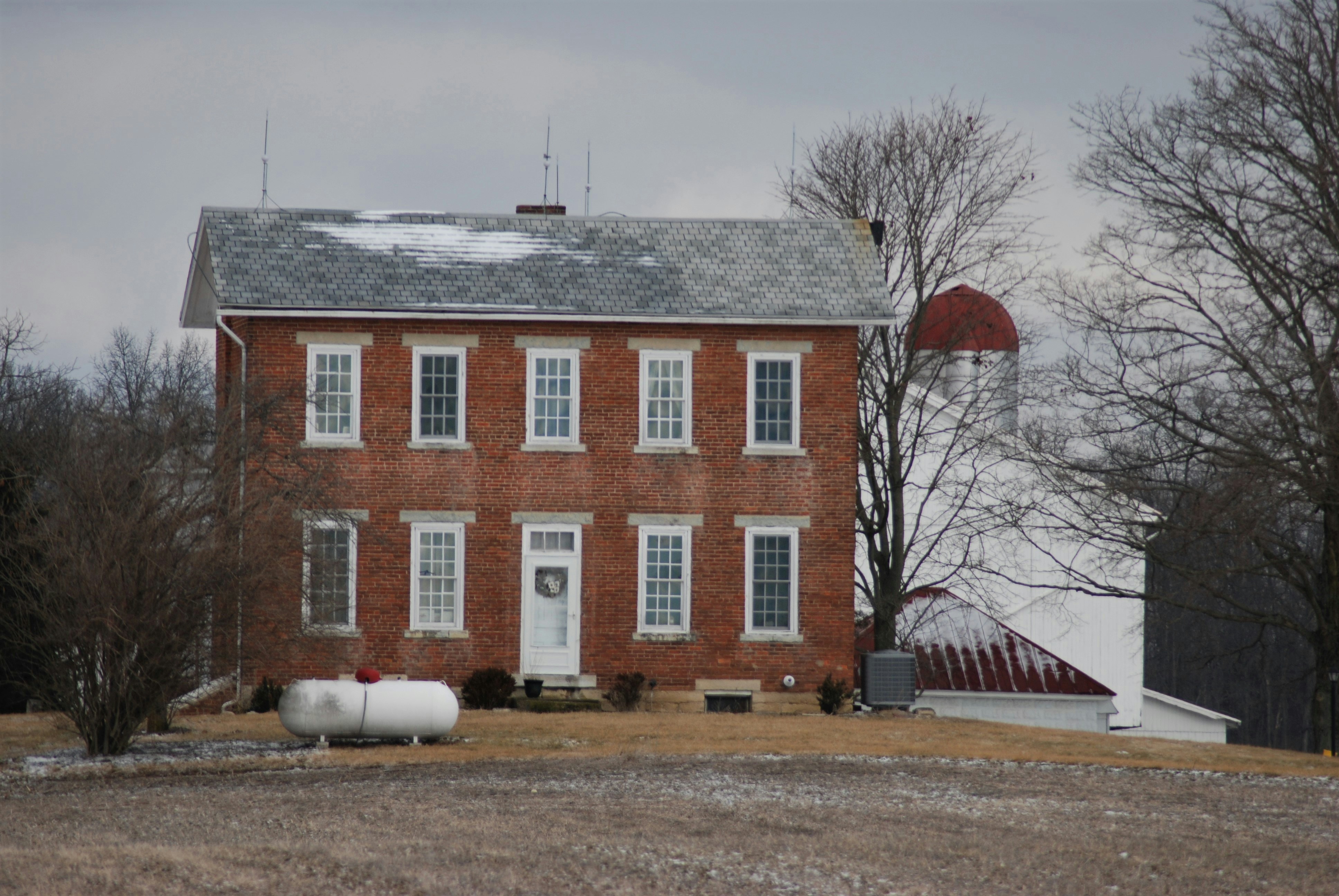 Une maison en briques rouges avec une porte et des fenêtres blanches ...